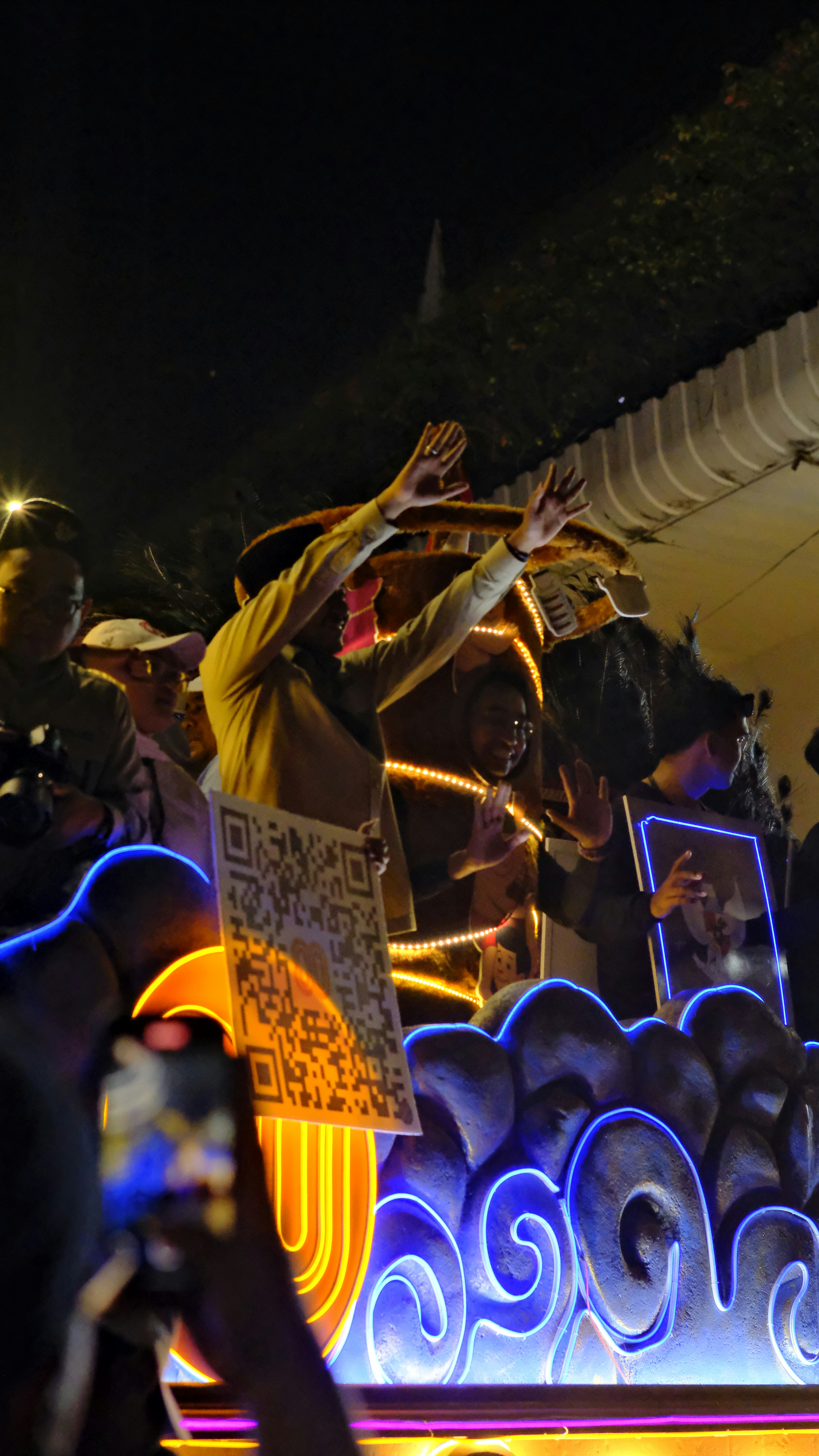 Midnight Neon Parade: Hands Raised Above a Wave-Pattern Float