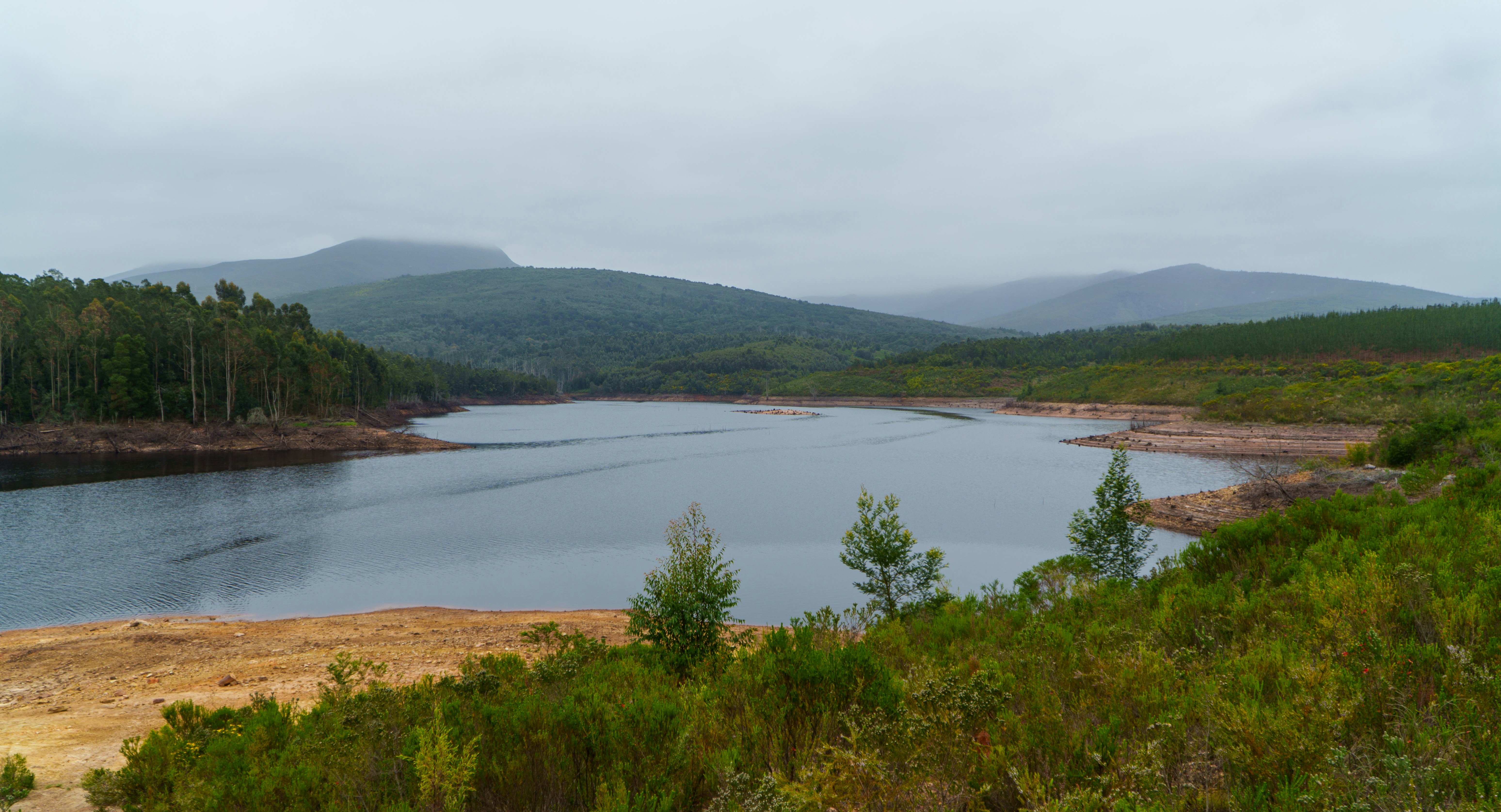 A calm lake surrounded by lush green hills and trees