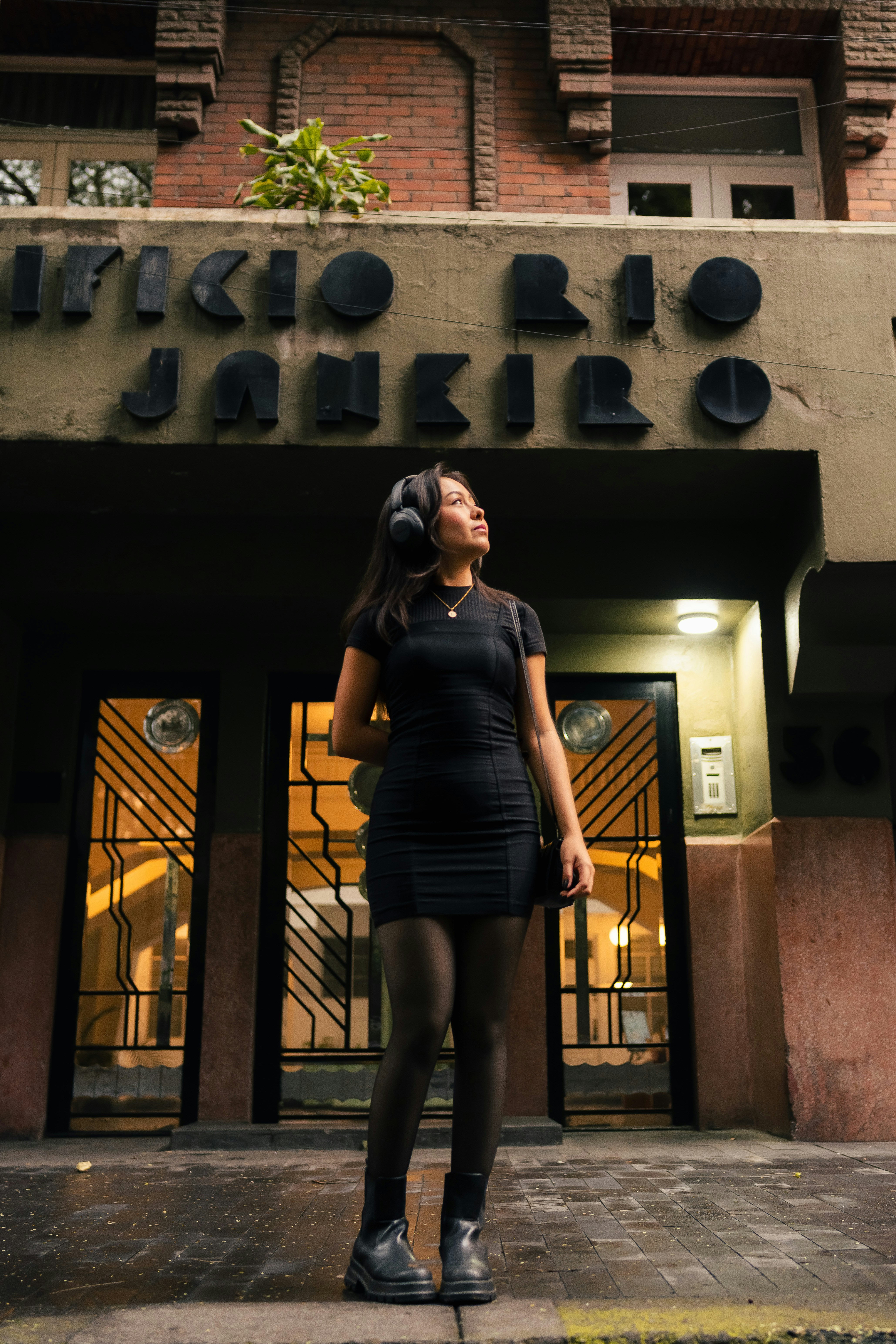 Headphones at Dusk: A Solo Portrait Beneath a Brick-Facade Backdrop