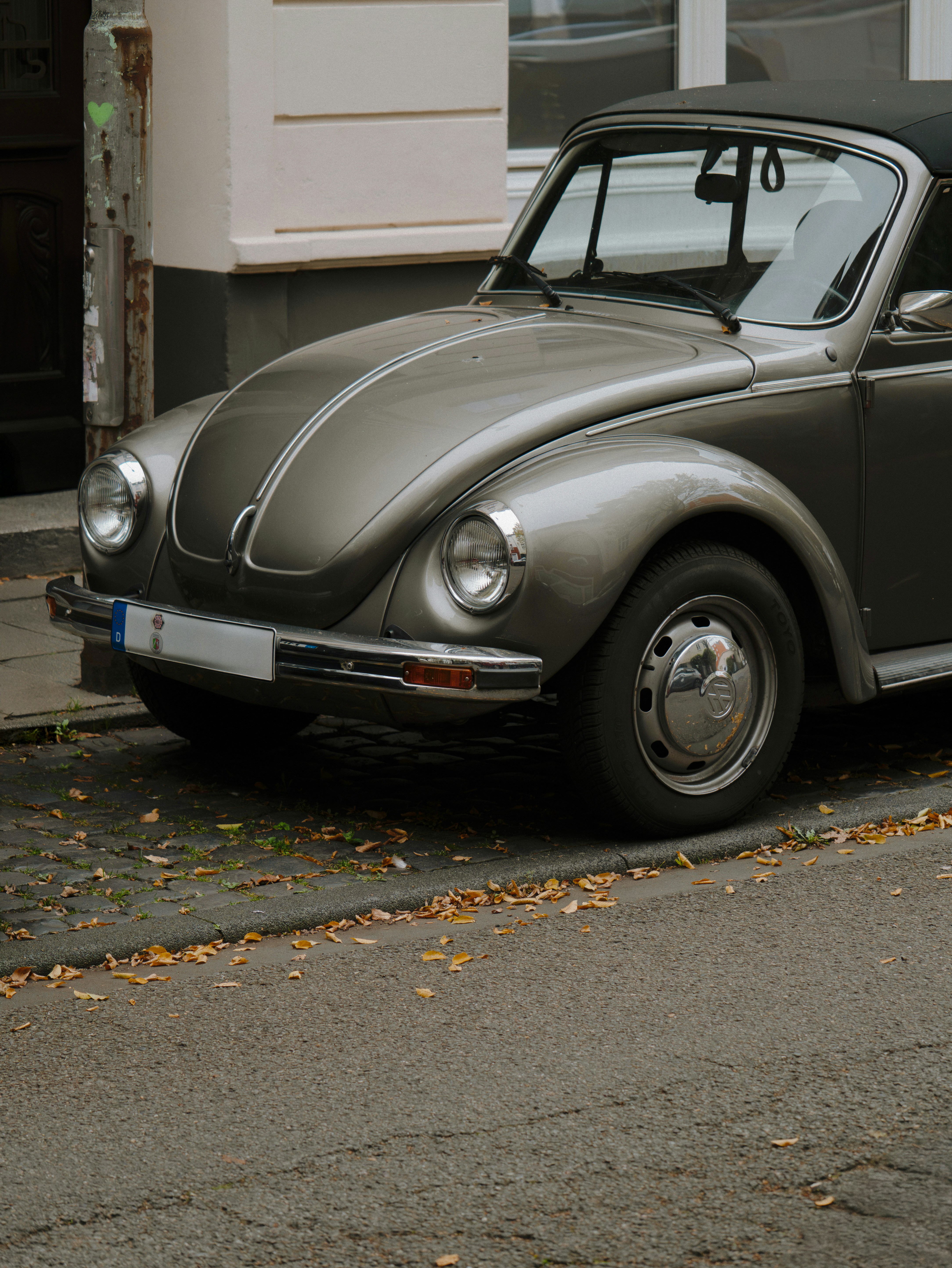 A classic grey convertible volkswagen beetle parked on street.