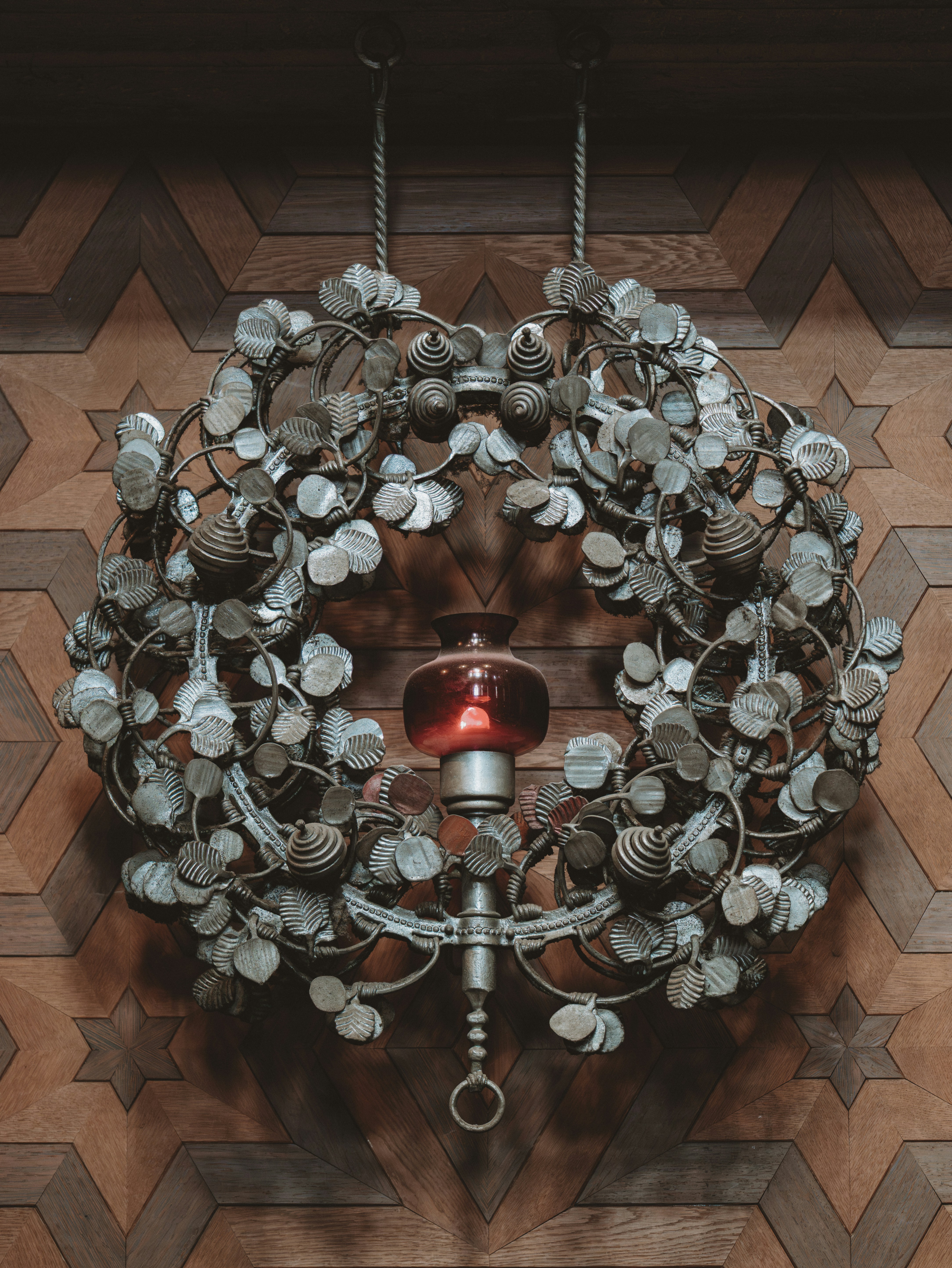 Ornate metal wreath with red glass lamp