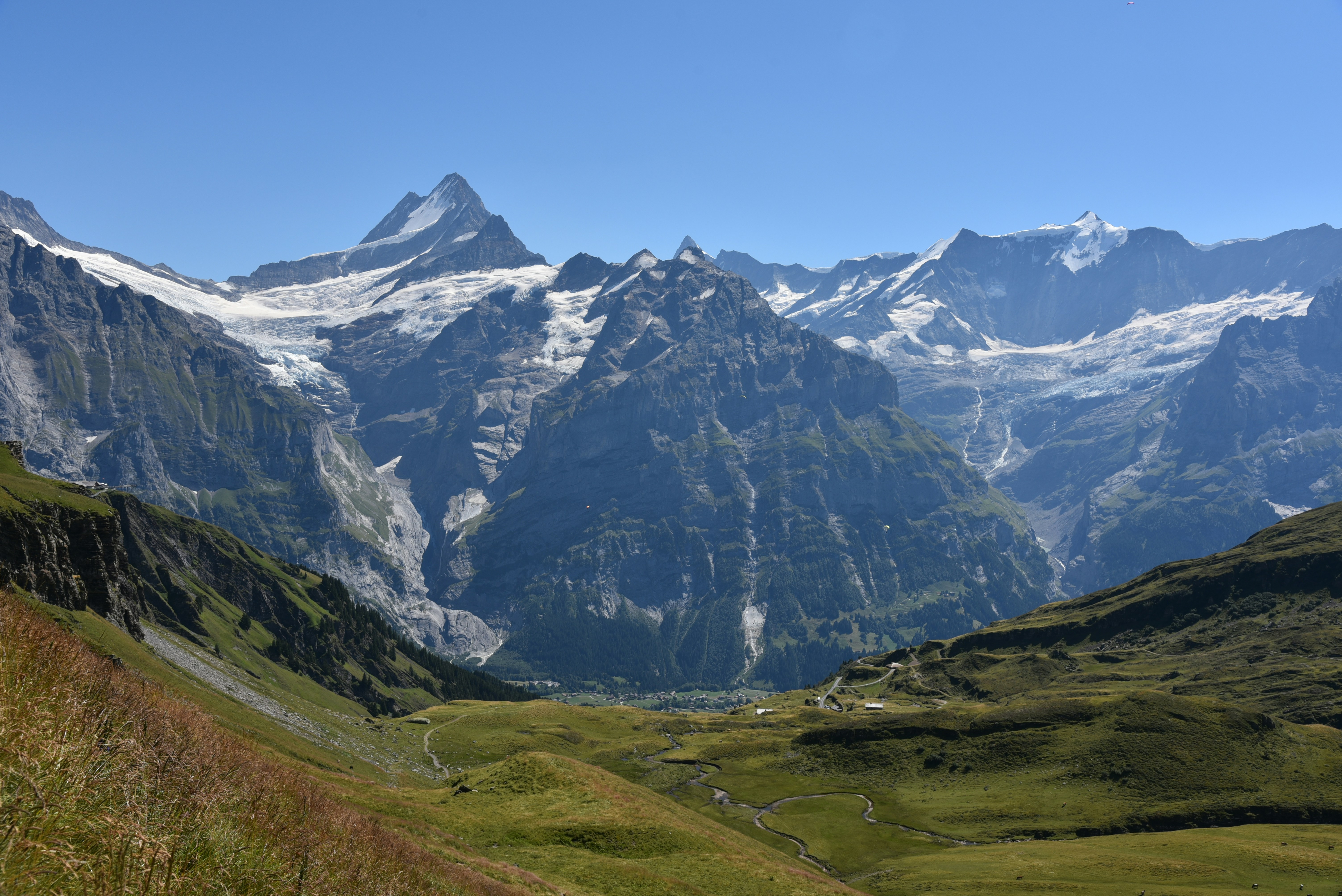 Vast mountain landscape showcasing towering peaks and glacial formations under a clear blue sky.