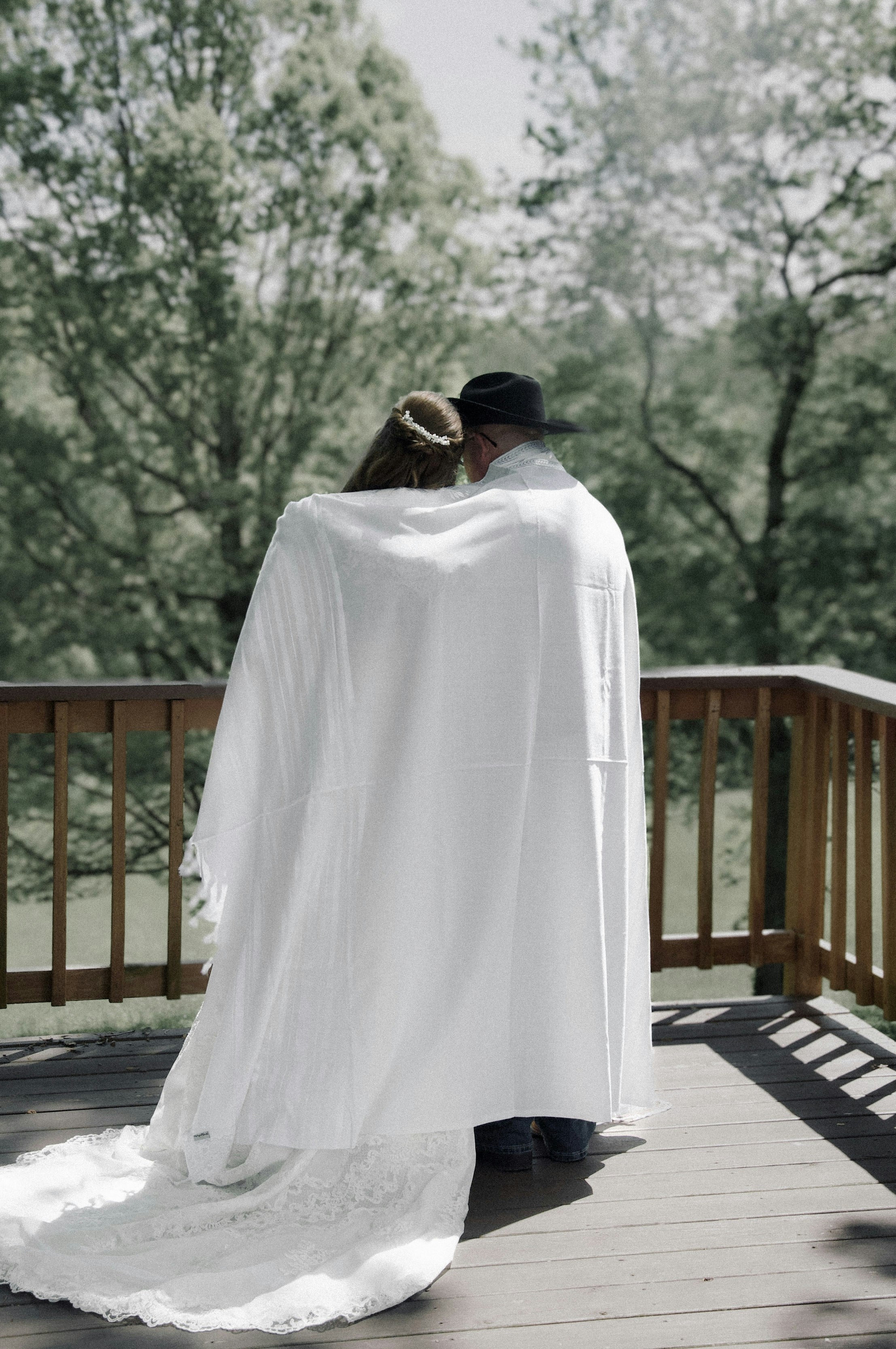 Couple in wedding attire sharing a moment on a deck.