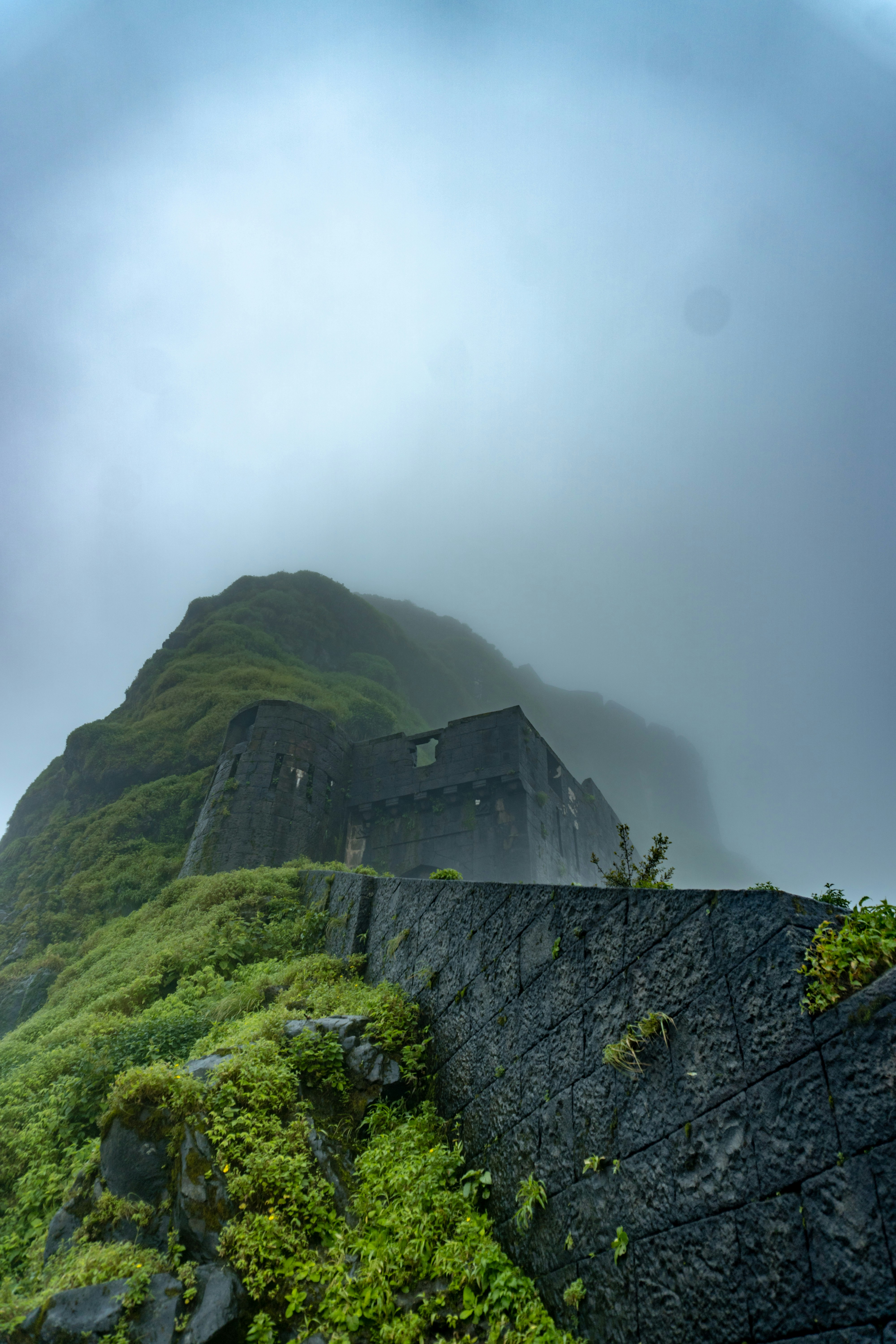 Ancient stone ruins on a misty, green mountain peak.