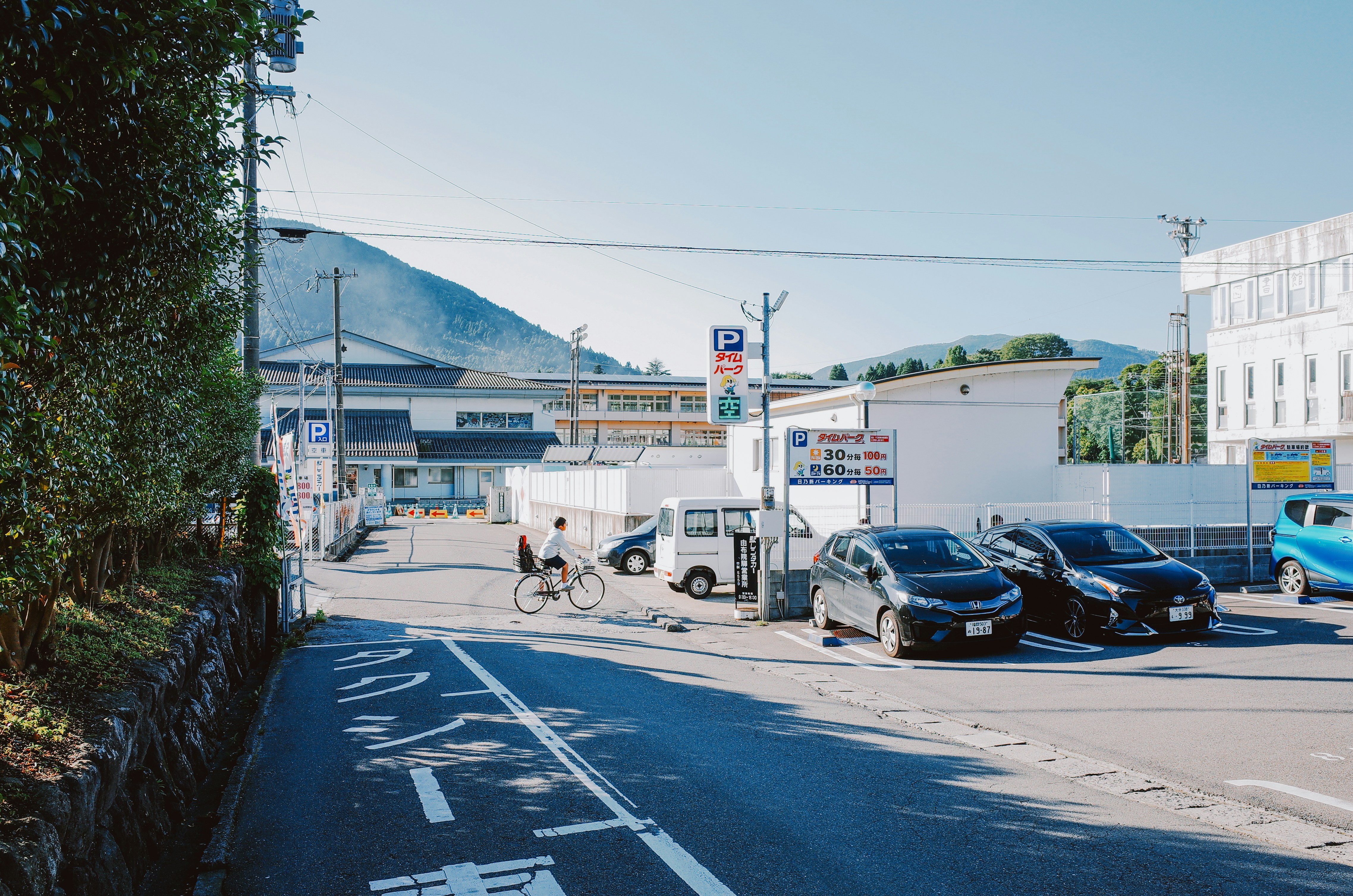 Sunlit Street Corridor: A Quiet Moment Between Cars and Hills