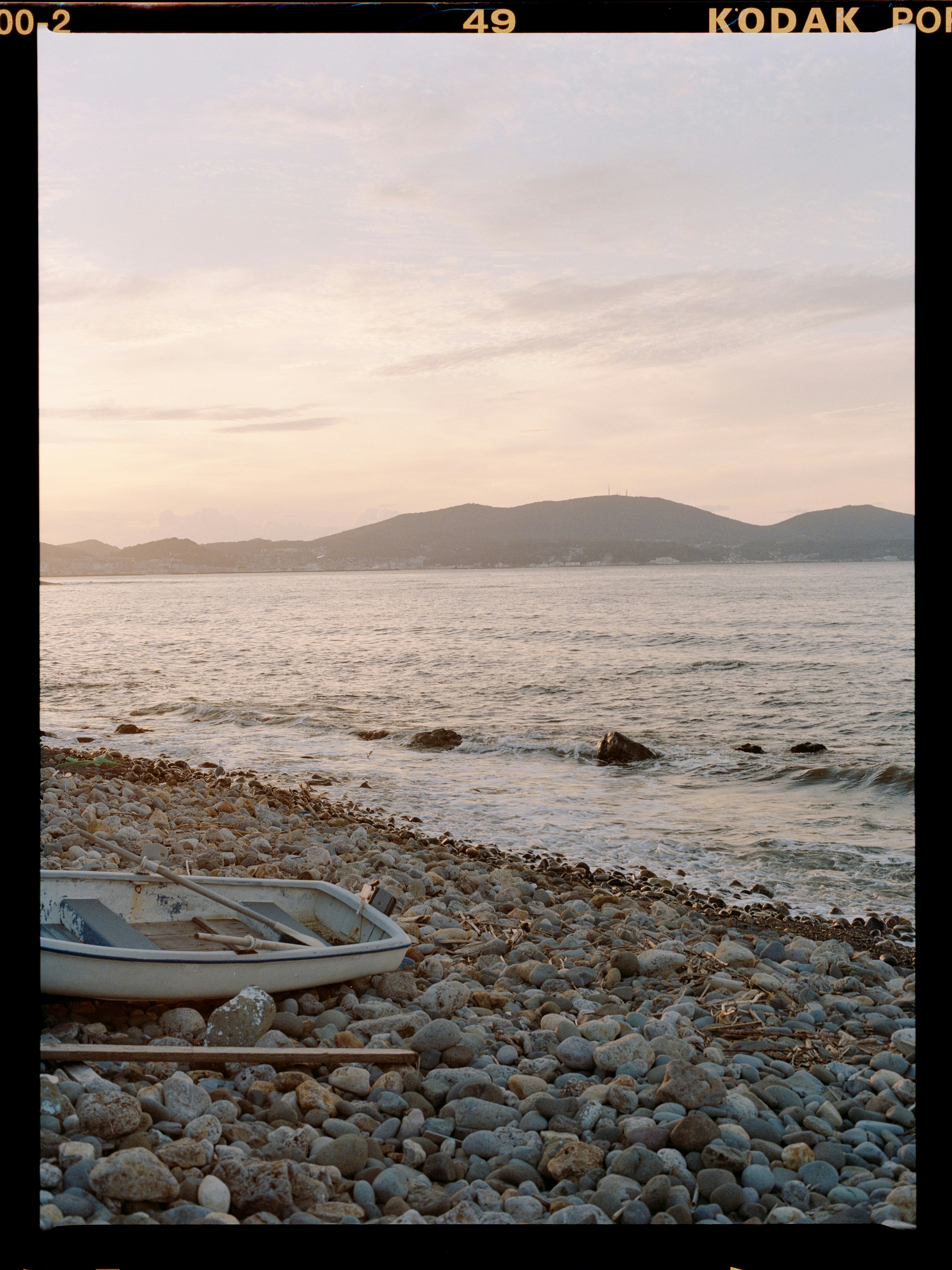 🎞️ Kodak Professional Portra 800｜🧪 Fuji Hunt C-41｜🖨️ EOS R6 + RF 100mm f/2.8L Macro｜📷 Mamiya 645 Pro + Mamiya-Sekor 80mm 1:1.9 | A small boat rests on a rocky shore at sunset.