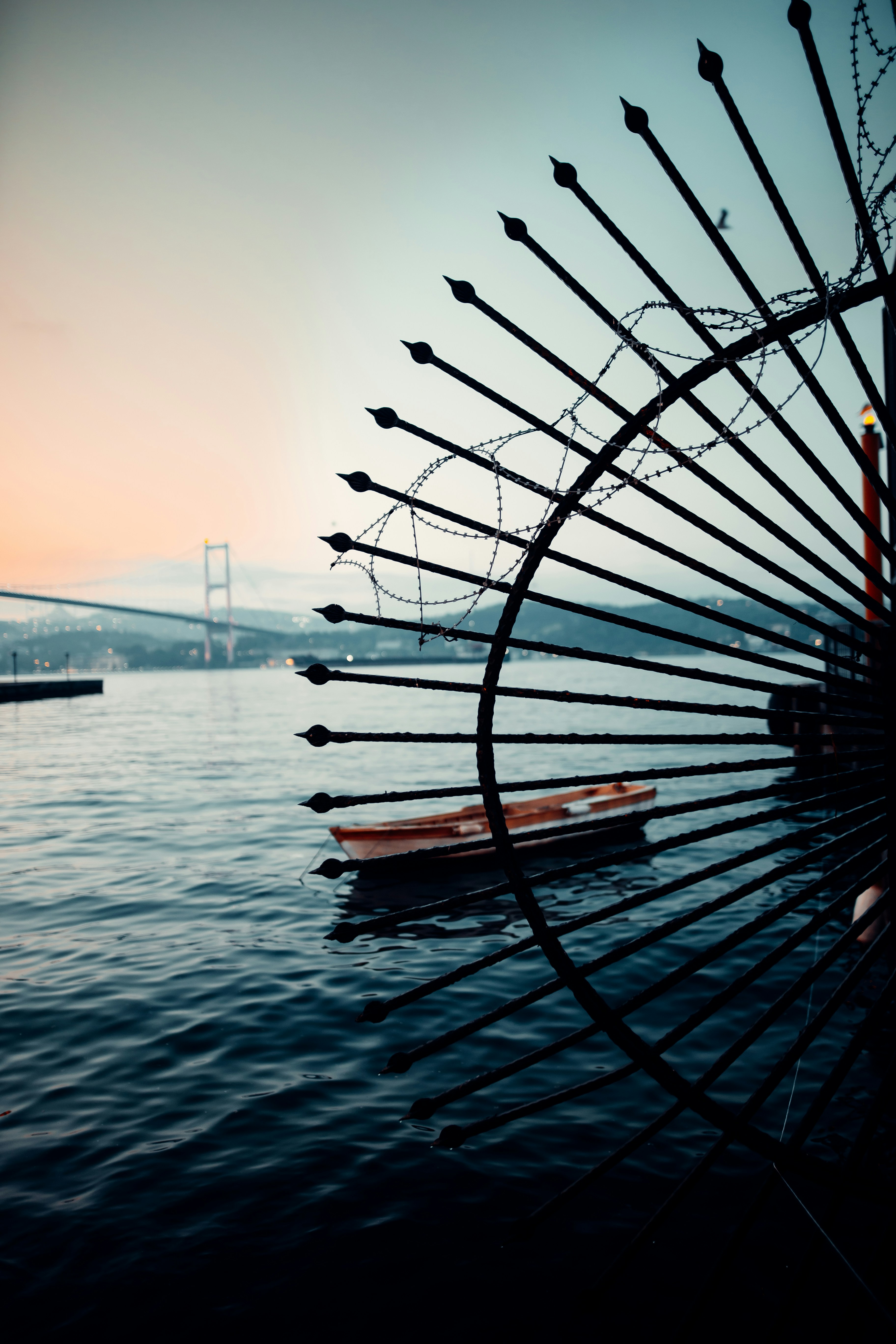 A small boat floats on the water near a bridge.
