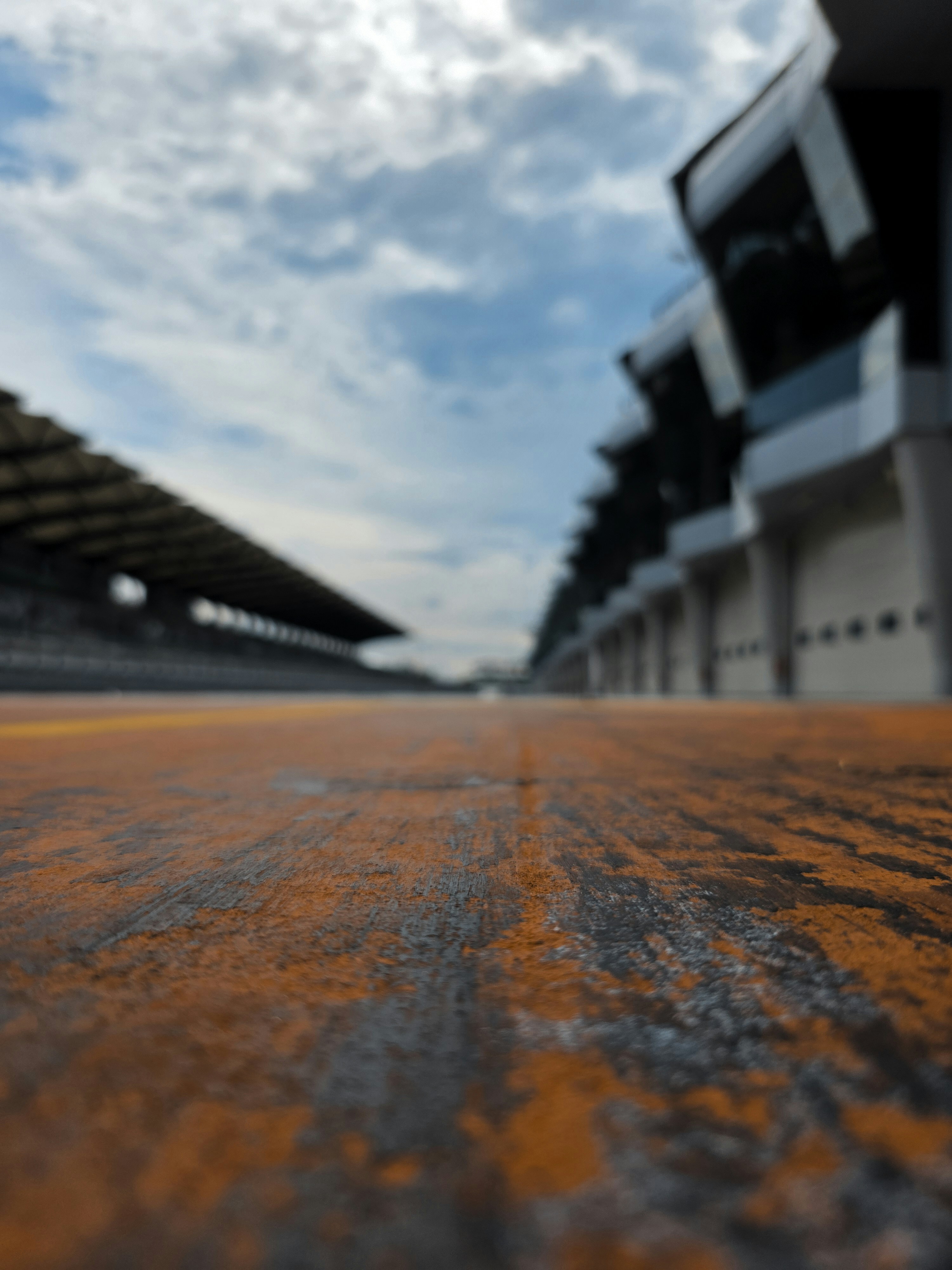 Pit lane at Sepang International Circuit | Orange textured surface leading to grandstands and buildings