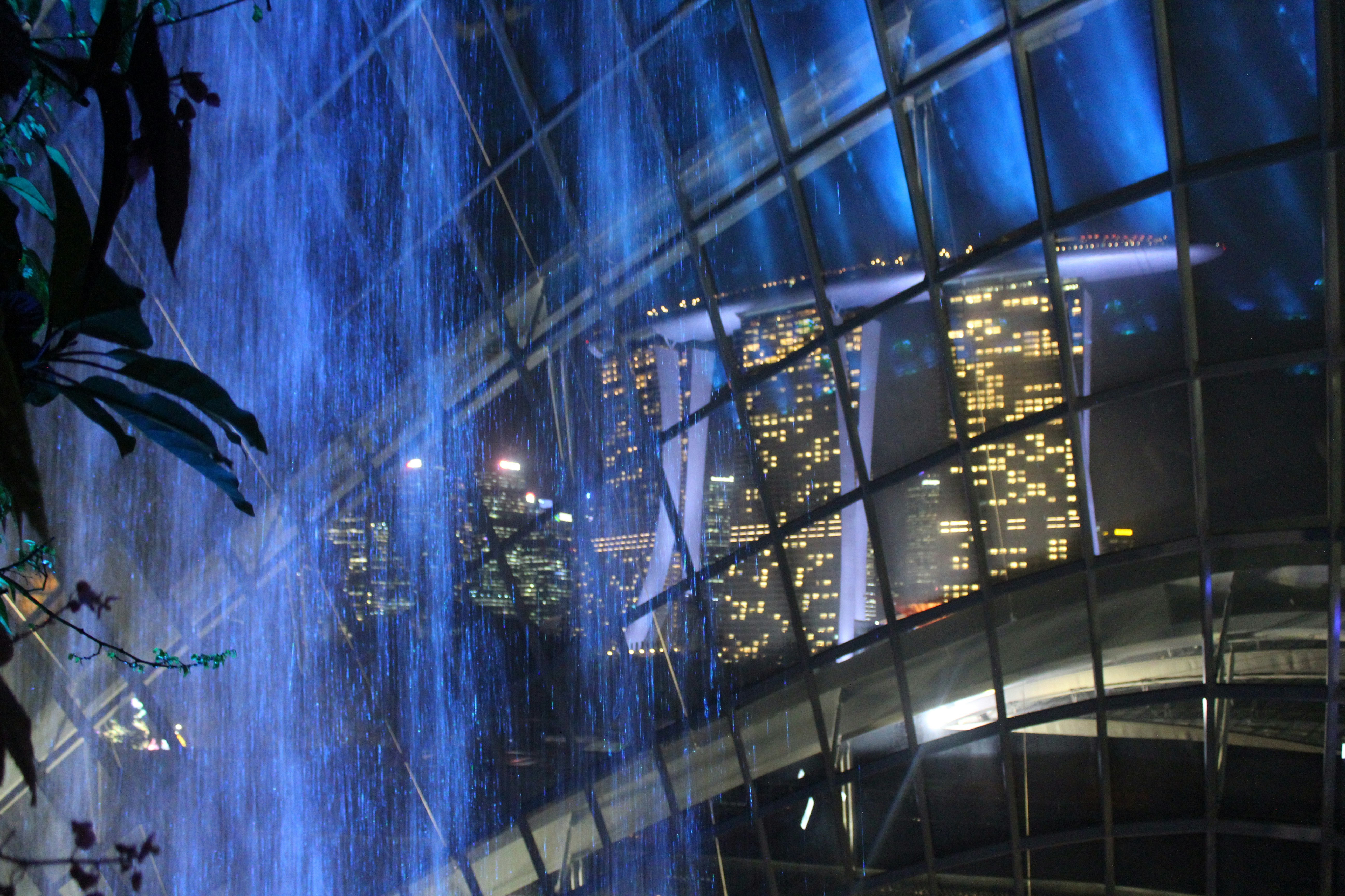 Blue Cascade Framing a Nighttime Skyline through a Glass Atrium