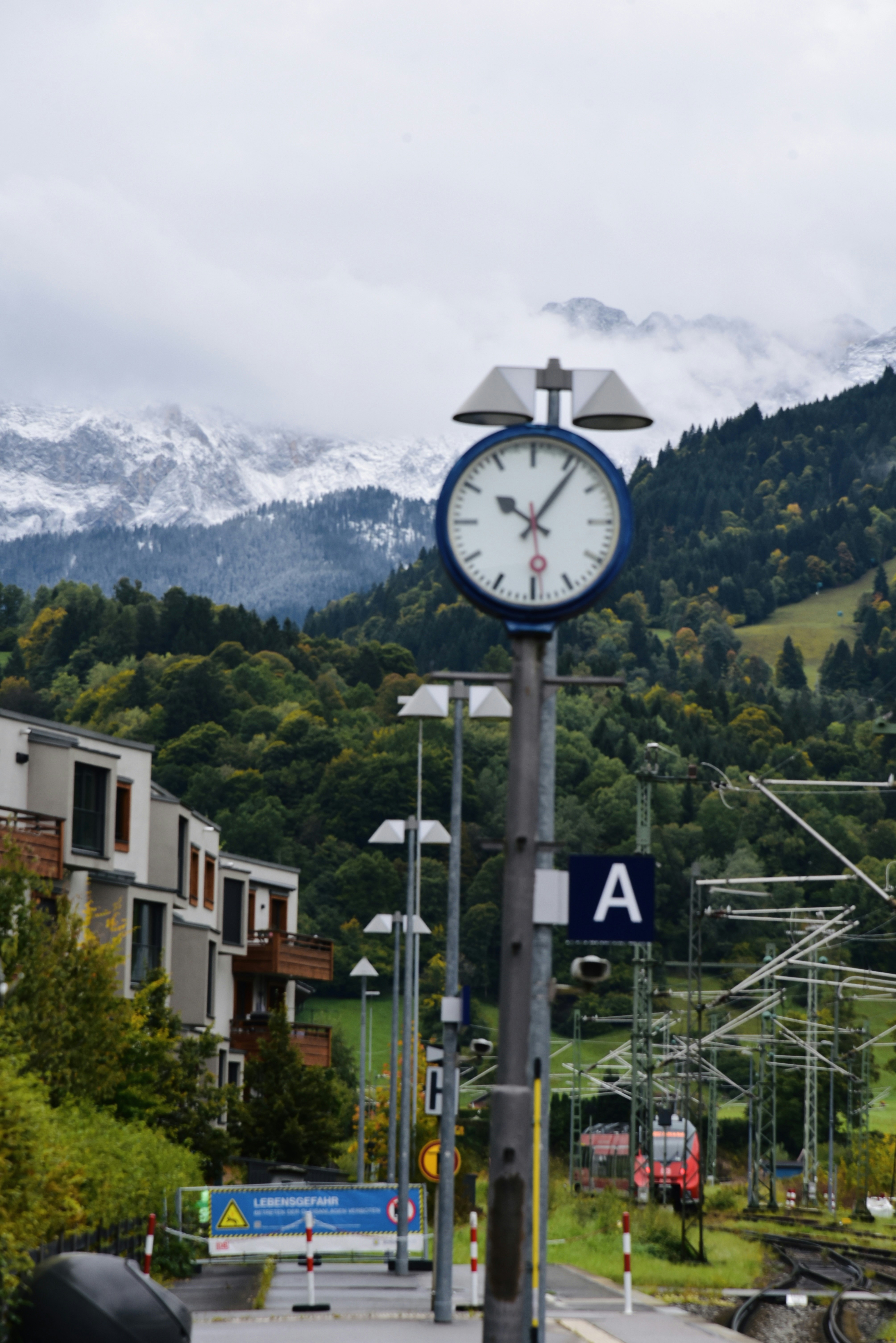Clock Face Over Rails: Alpine Station Amid Snow-Dusted Peaks