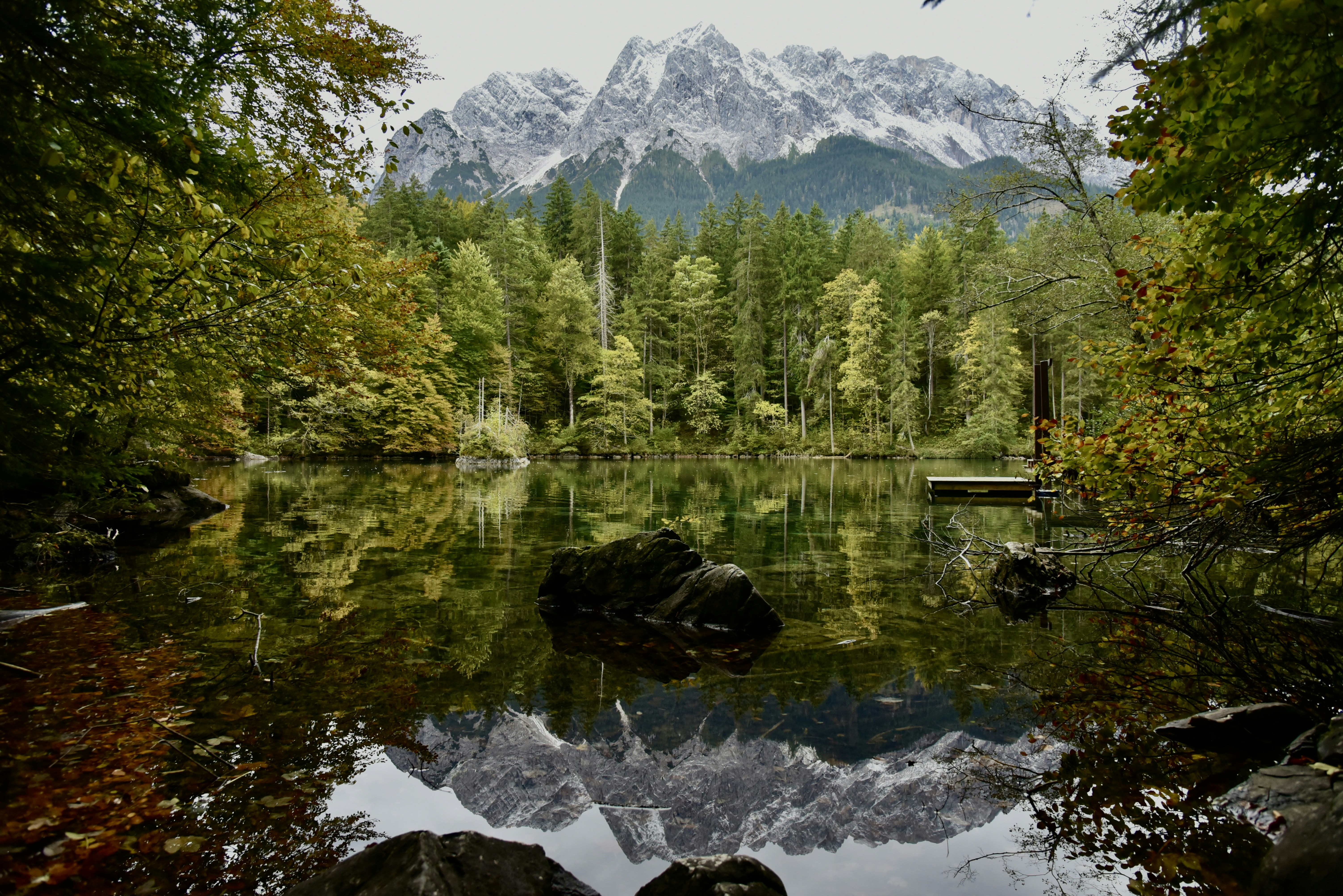 Tranquil lake surrounded by vibrant autumn foliage and majestic mountains reflecting in the water. Perfect harmony of nature's colors.