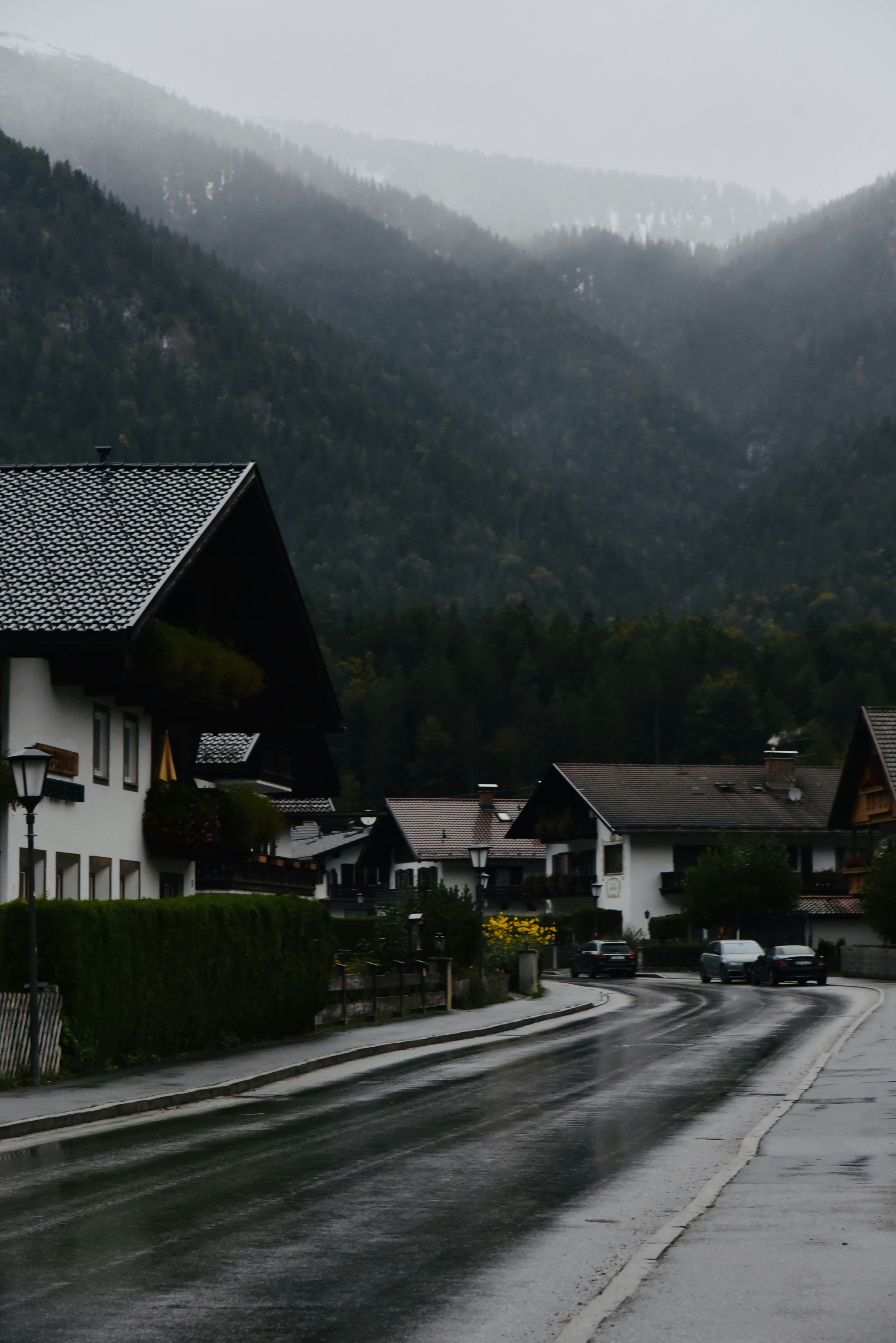 Wet street in a village with mountains in background.