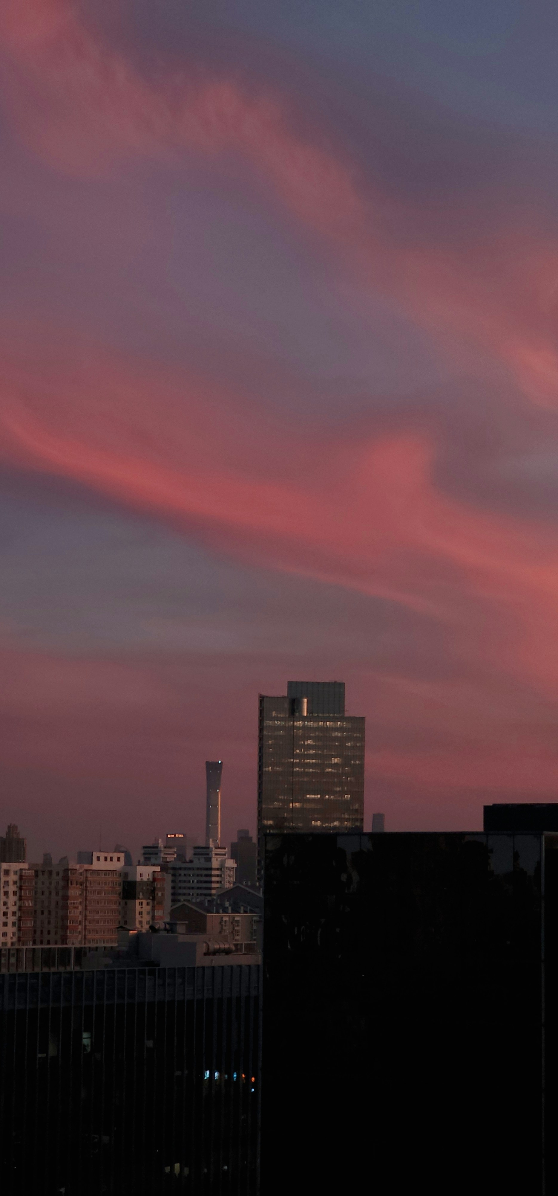 Vibrant sunset hues paint the sky above a bustling city skyline, showcasing a blend of modern architecture and natural beauty.