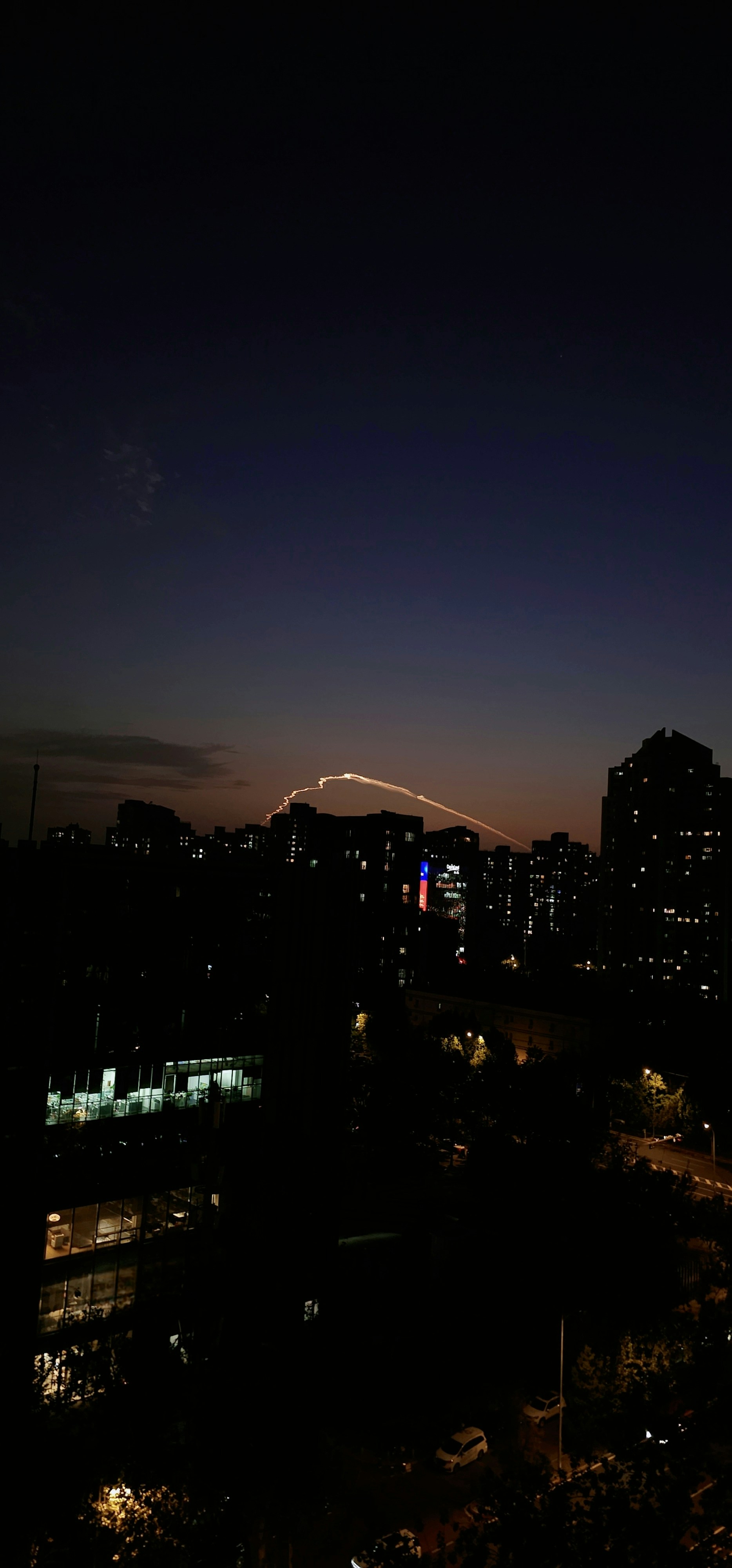 A Celestial Trail Over Urban Lights