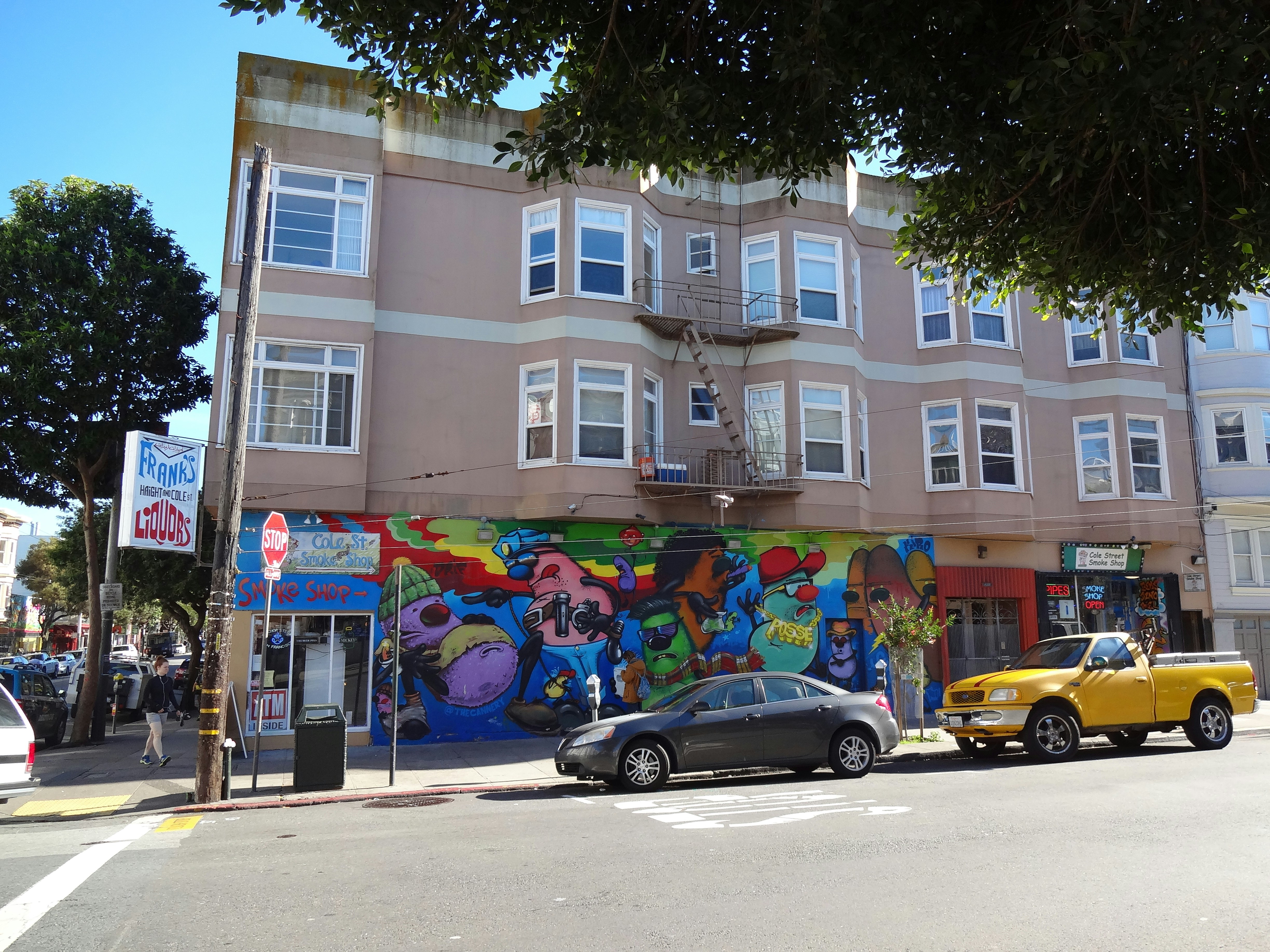 Colorful mural depicting playful characters on a city building, showcasing urban art culture. The scene captures the lively atmosphere of the neighborhood.