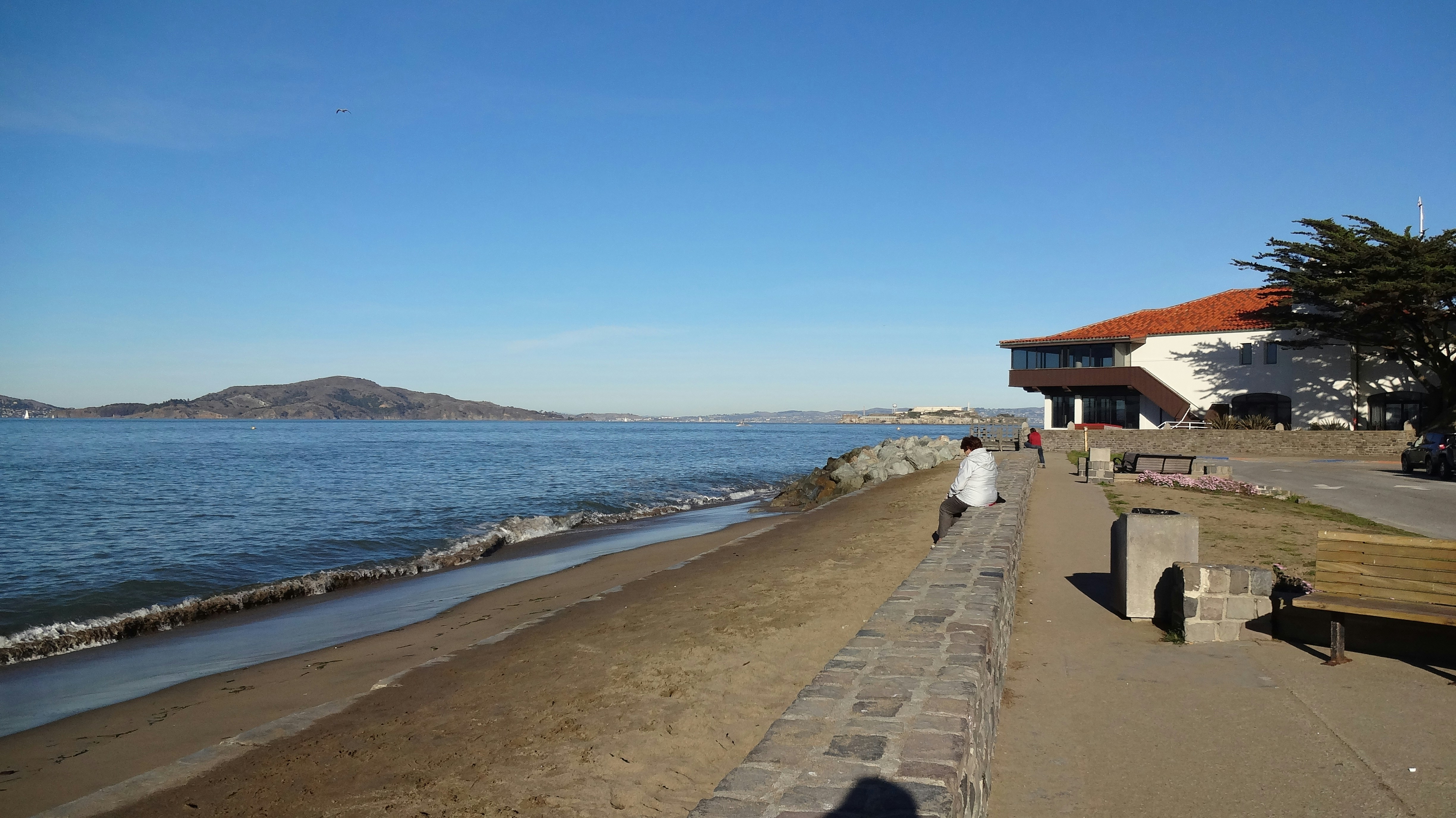 Sunlit Seawall Moment: A Quiet Figure by the Coastal Promenade
