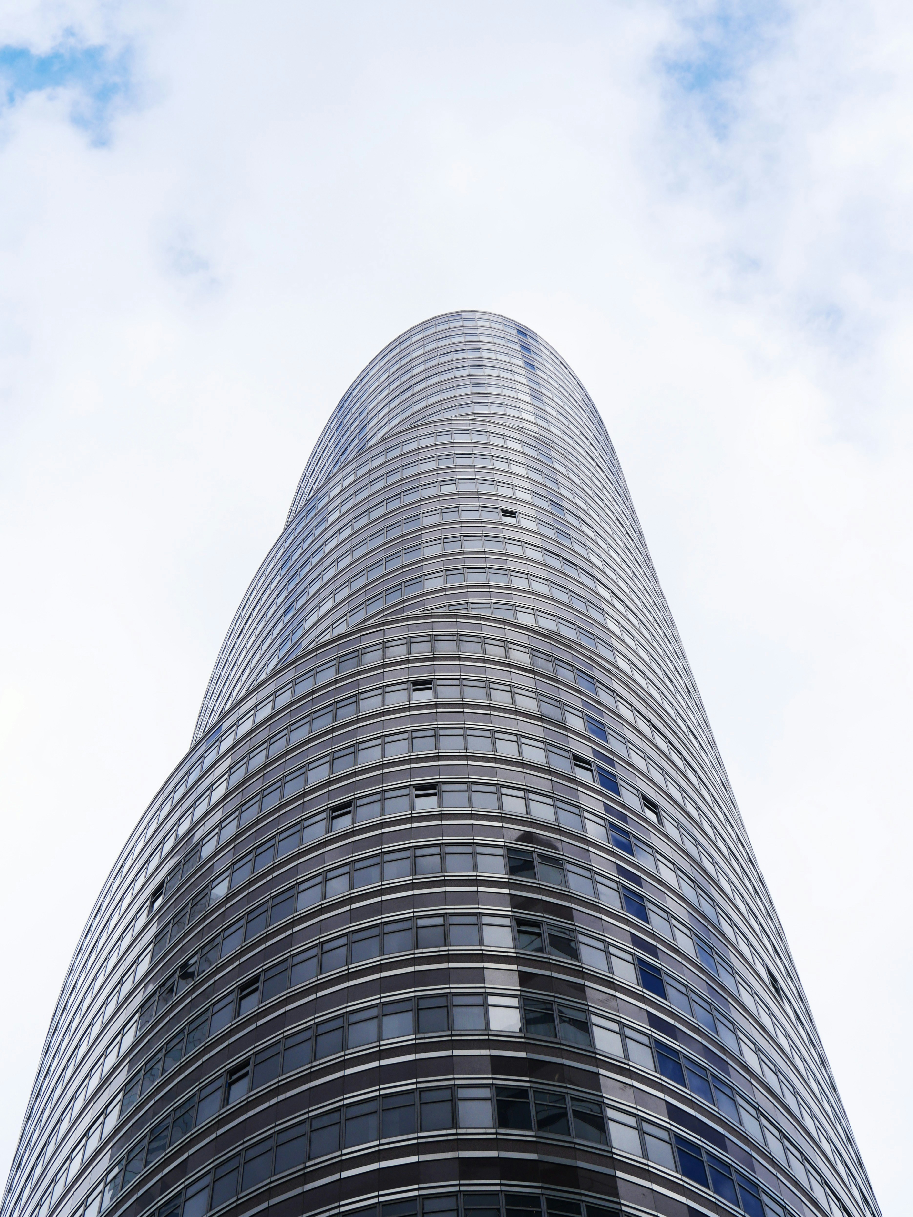 Modern skyscraper with curved glass facade against sky