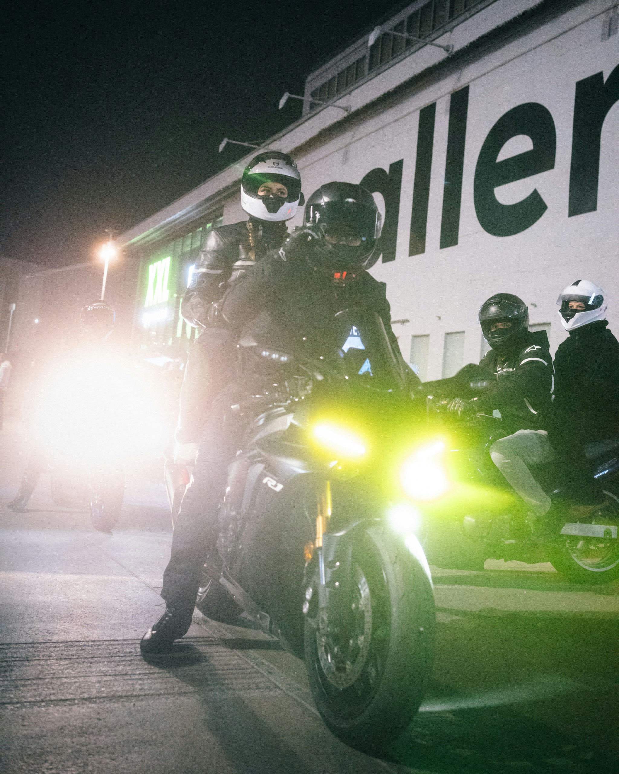 Riders Assemble: Night Sprint beside a neon-lit storefront
