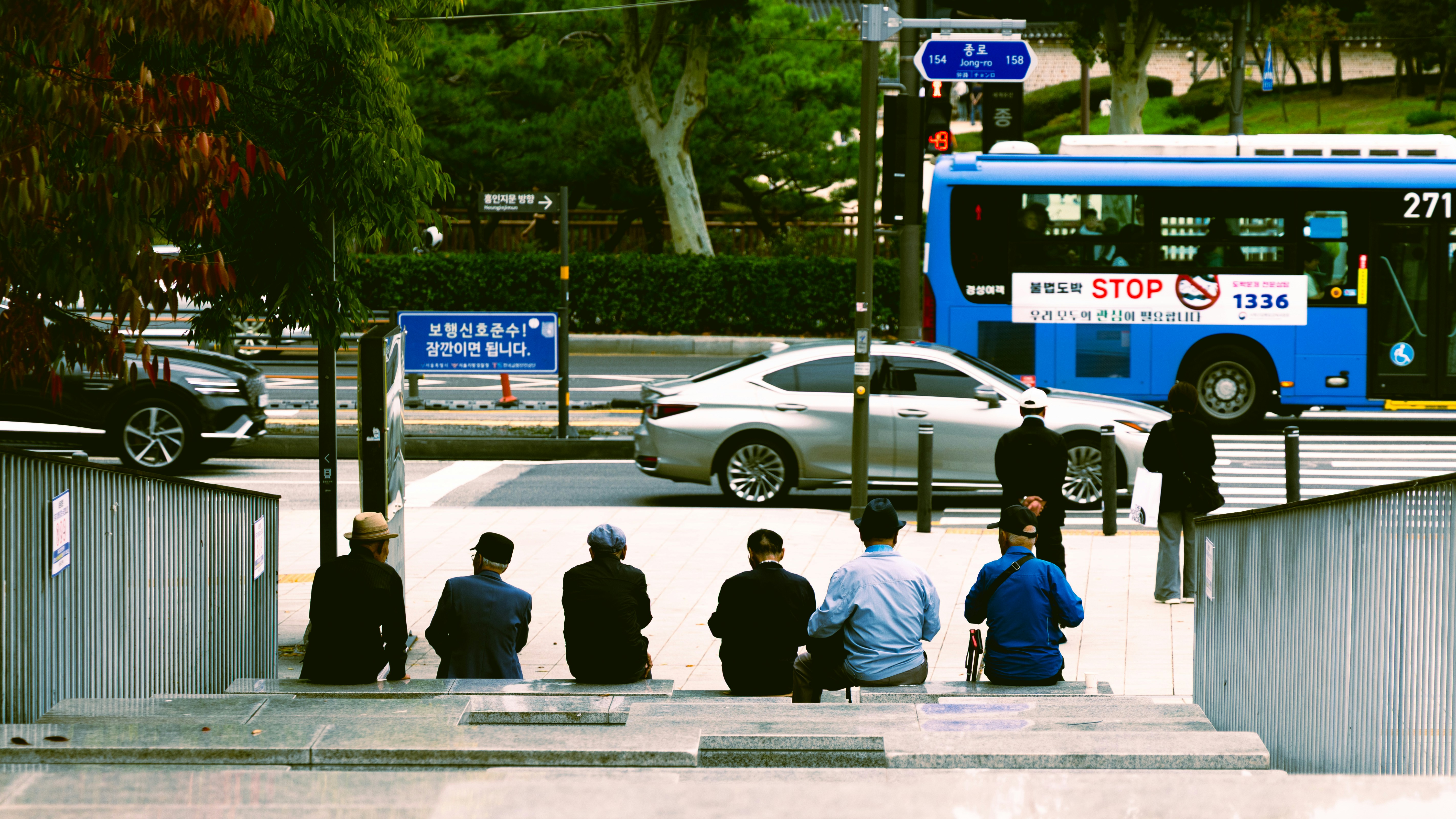 People sitting on stairs with city street in background