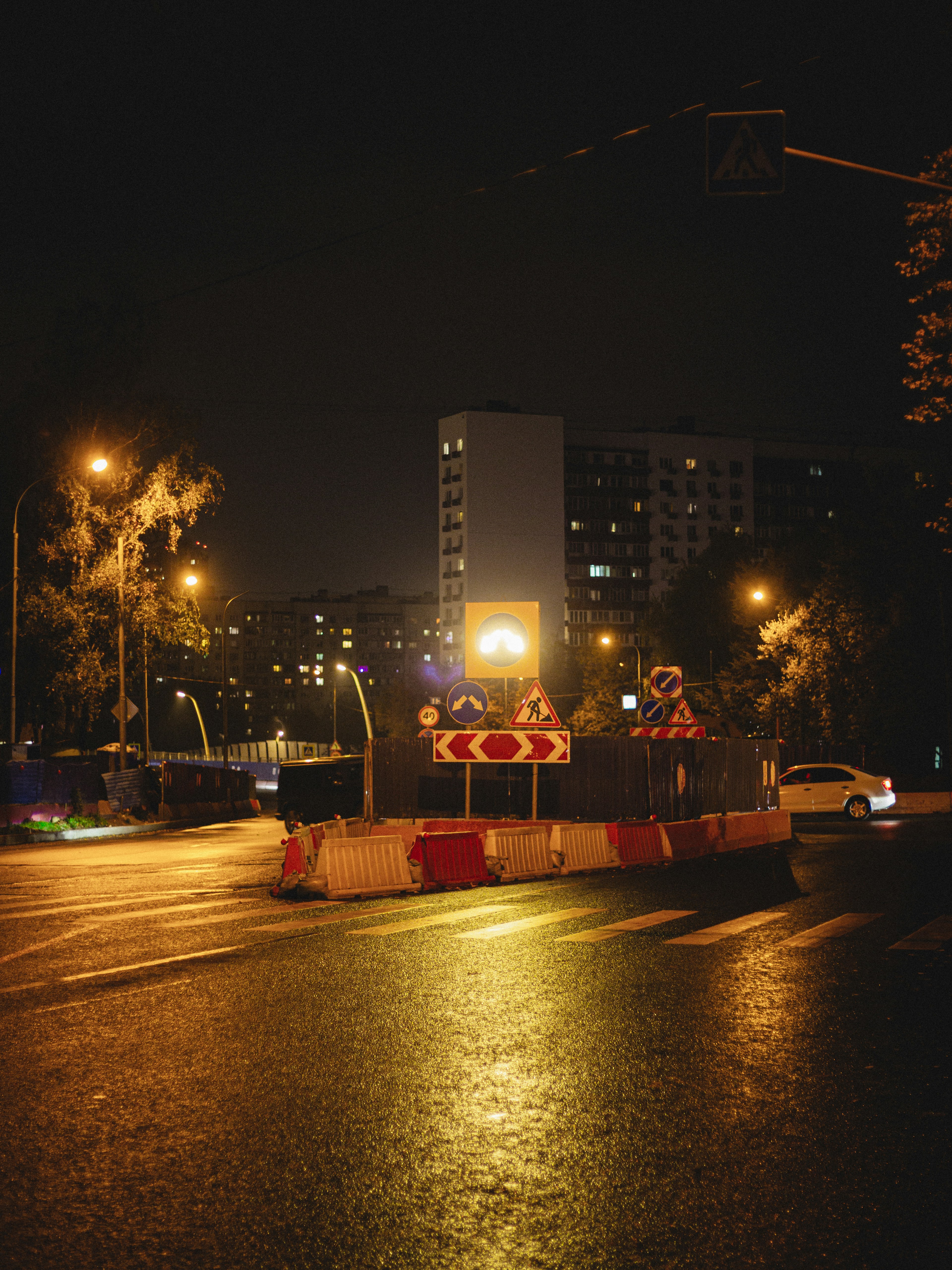 Road construction barriers at night with traffic lights.