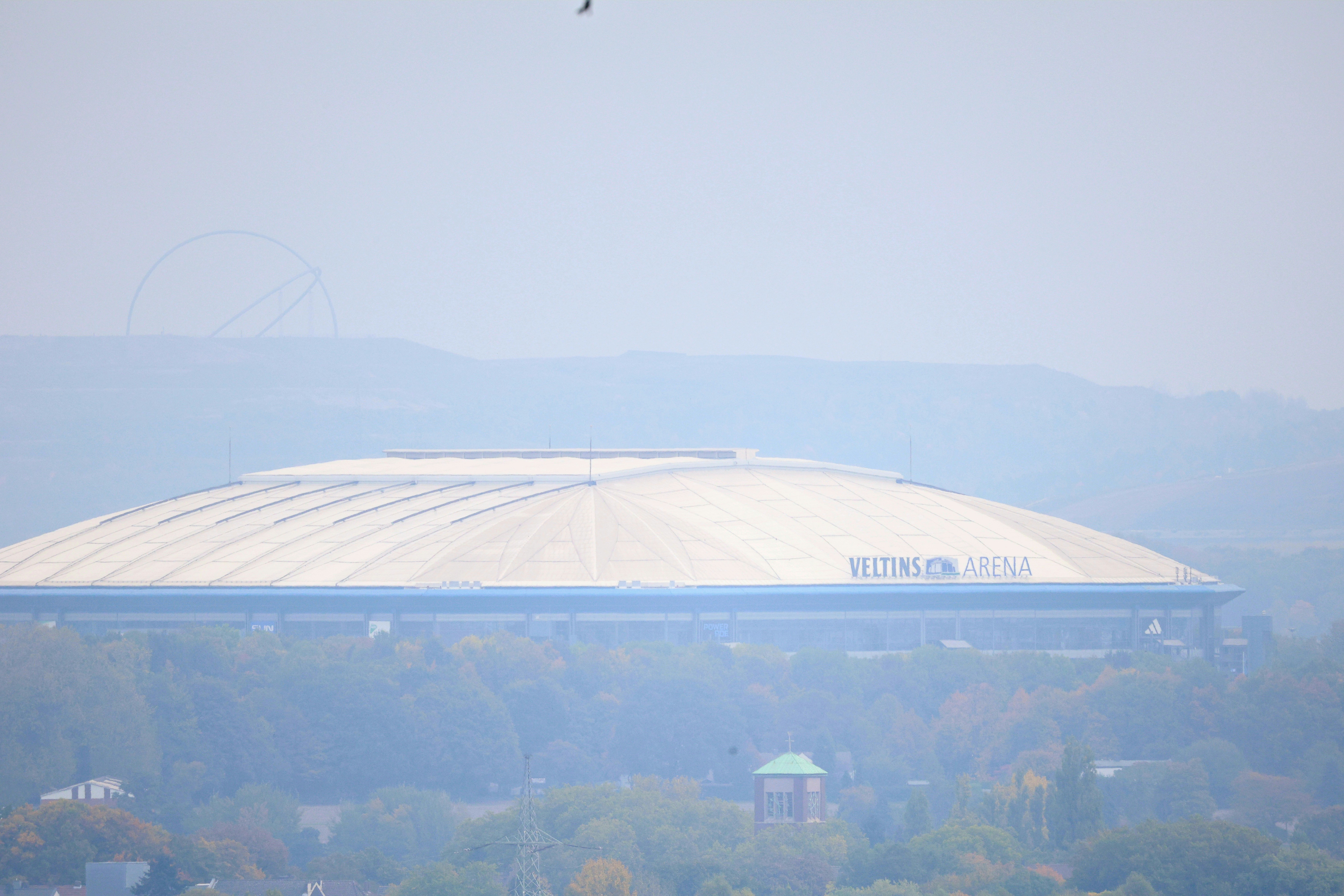 Modern stadium with a domed roof under a hazy sky.