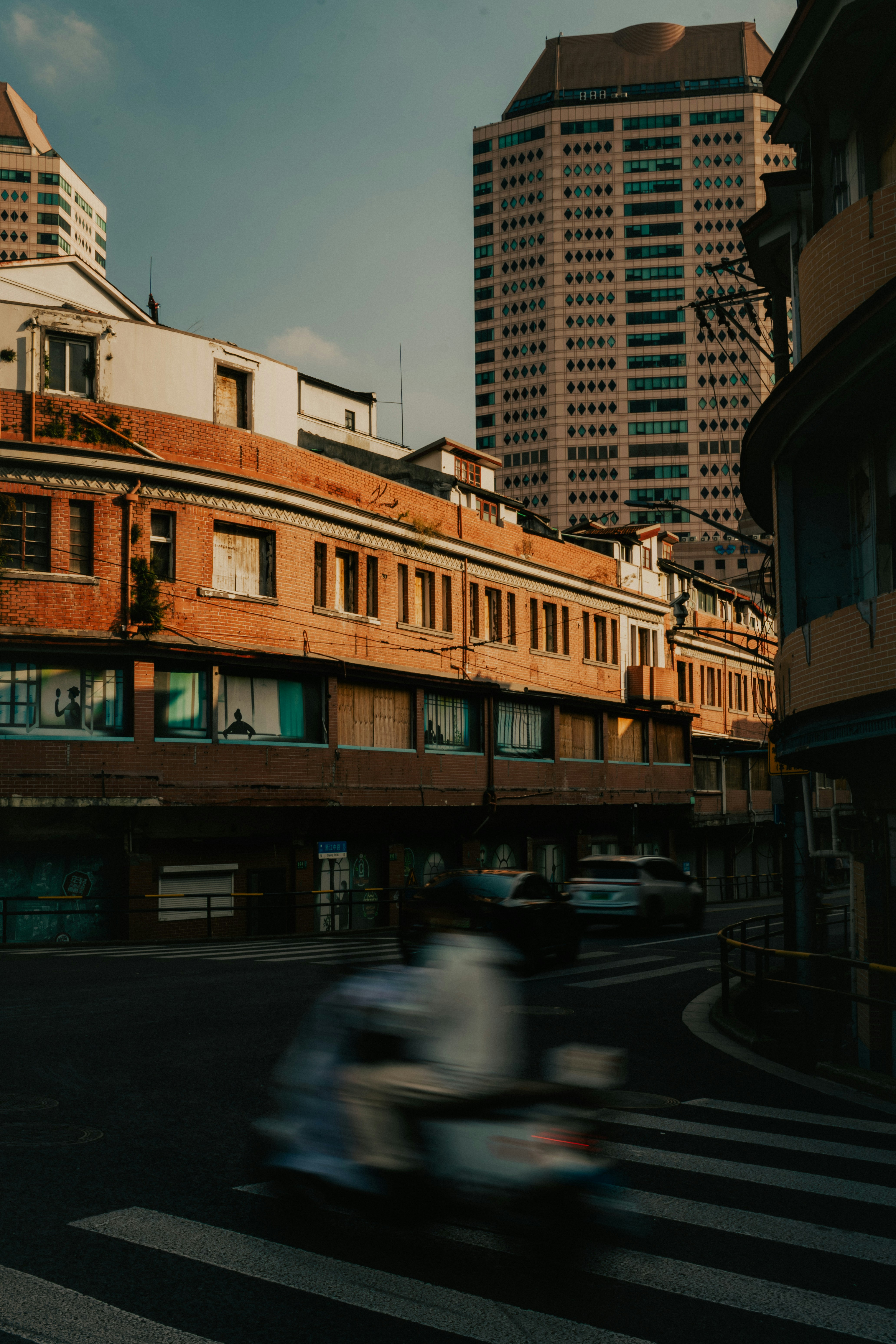 A busy cross | Motorcyclist crosses street in front of old buildings.