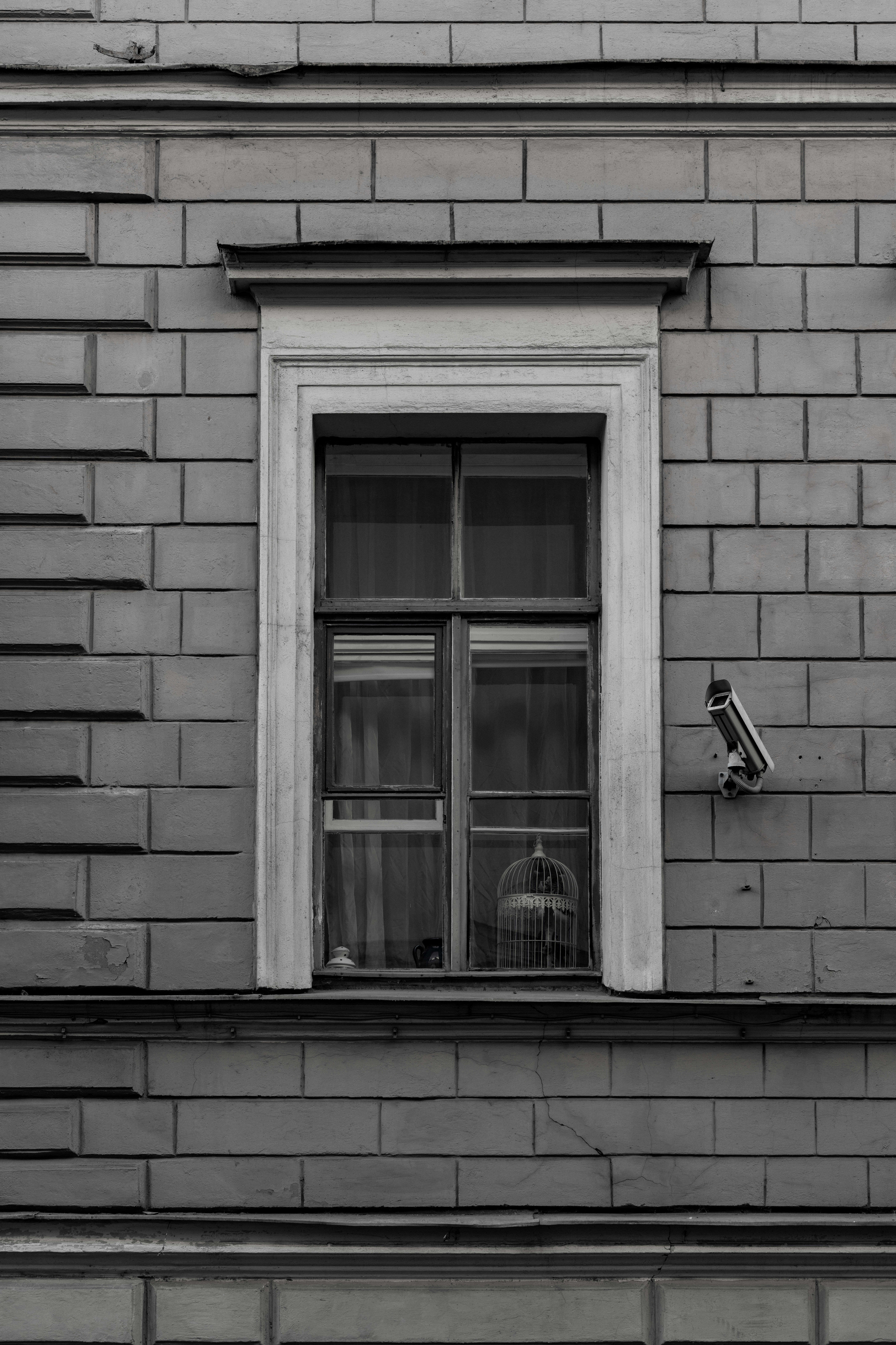 A window on a brick building with a security camera.