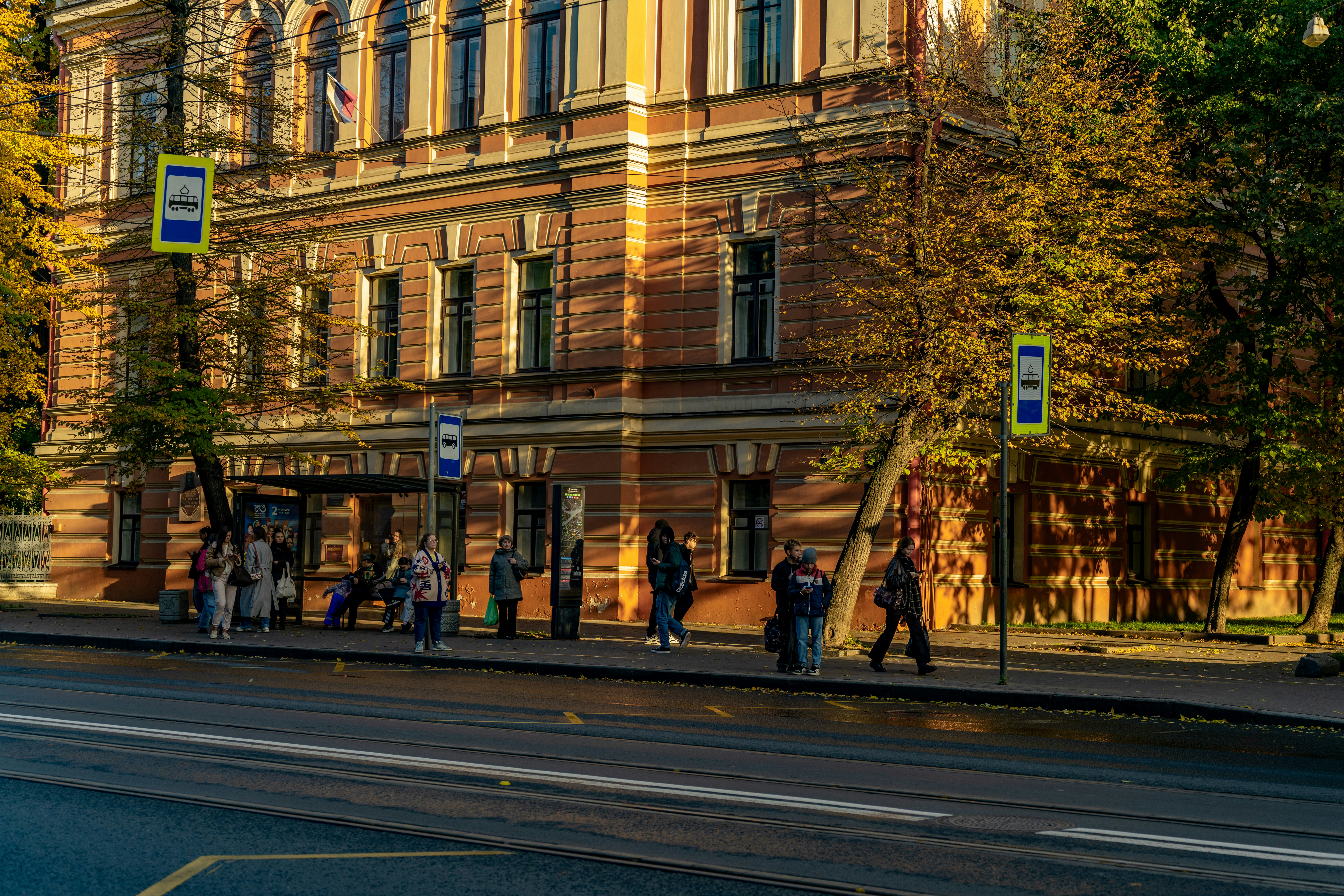 People wait at a bus stop near a building.