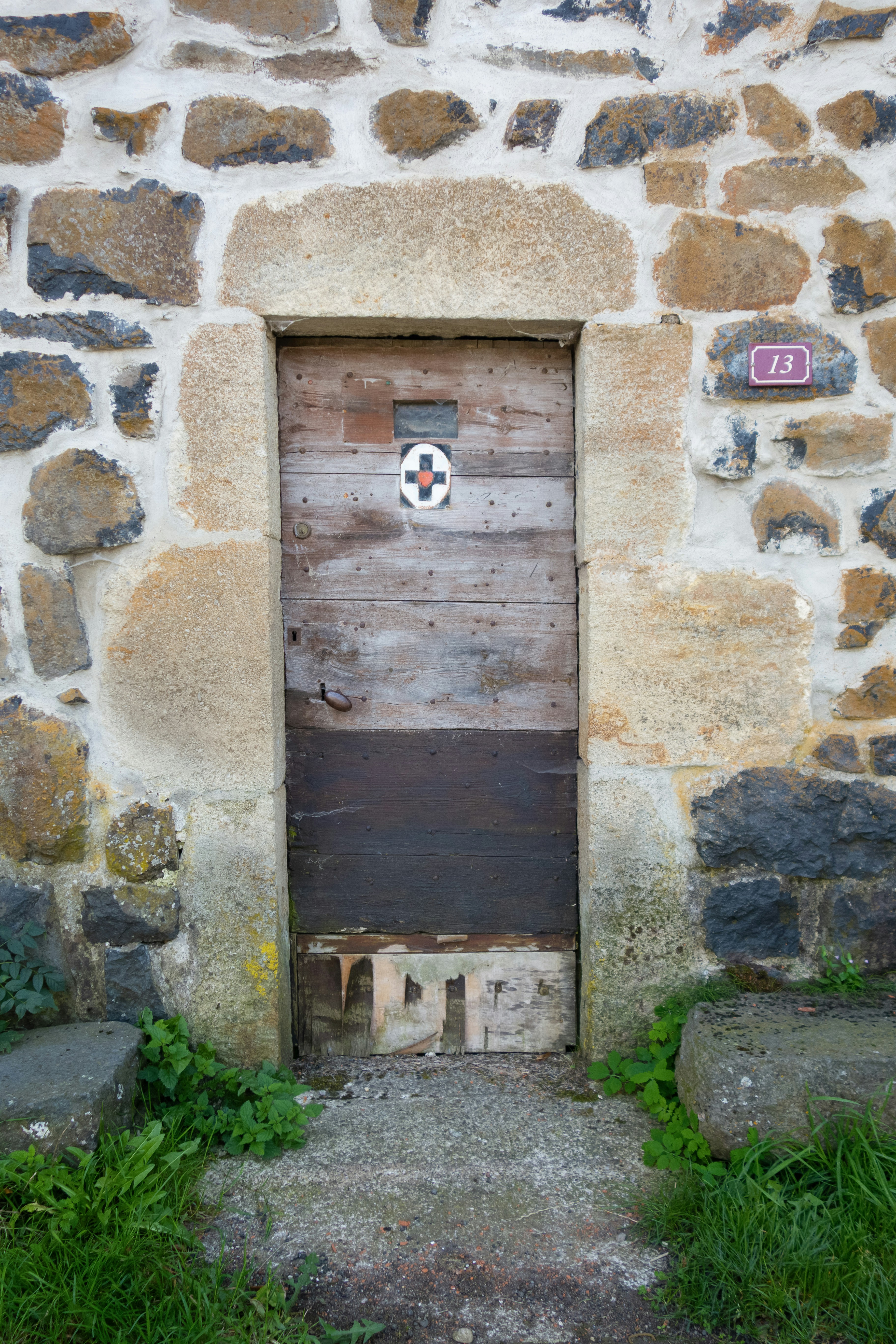 Timeworn Doorway Framed by Rustic Stonework and a Shield Emblem