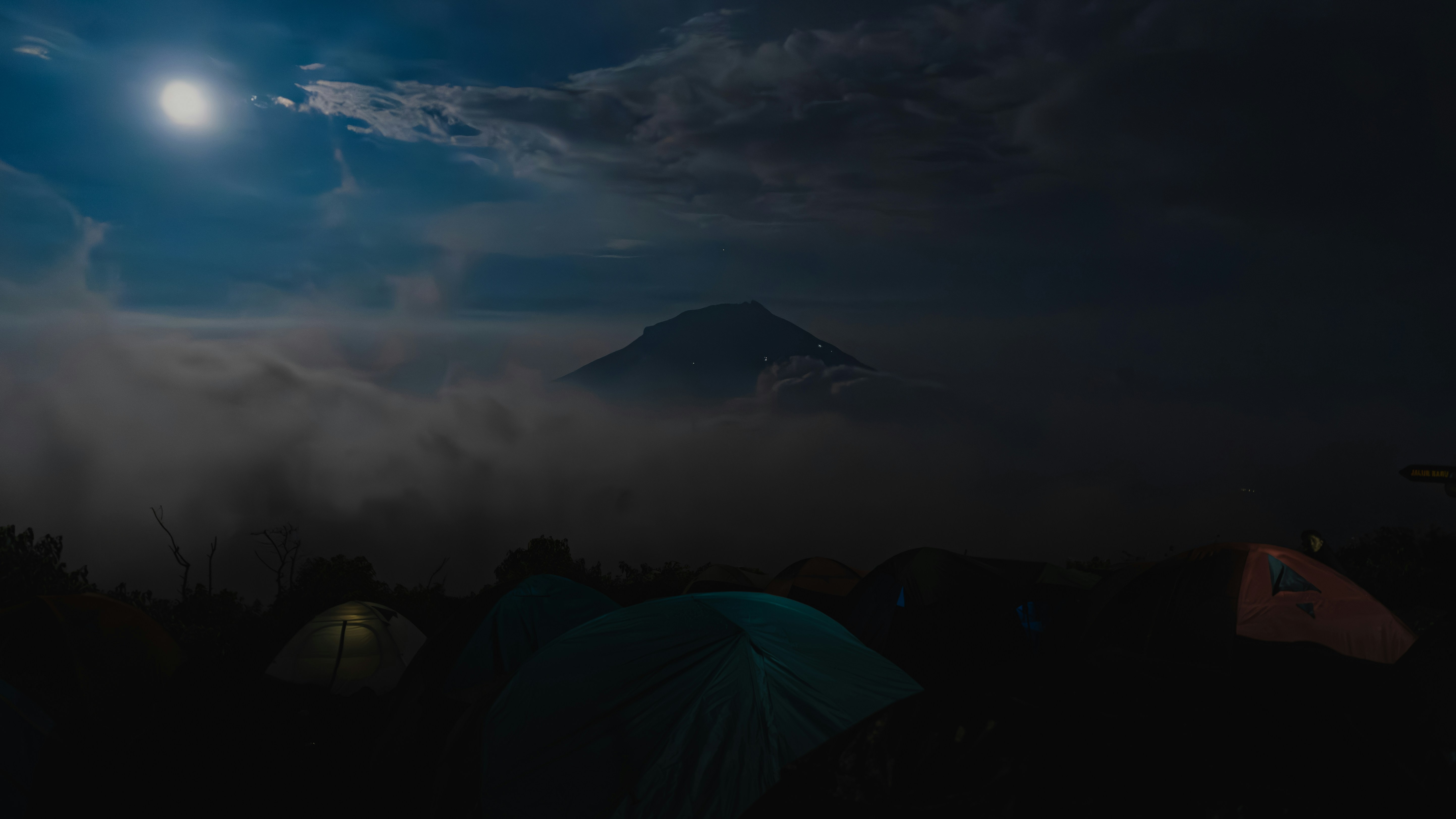Moonlit mountain peak above foggy campsite at campsite