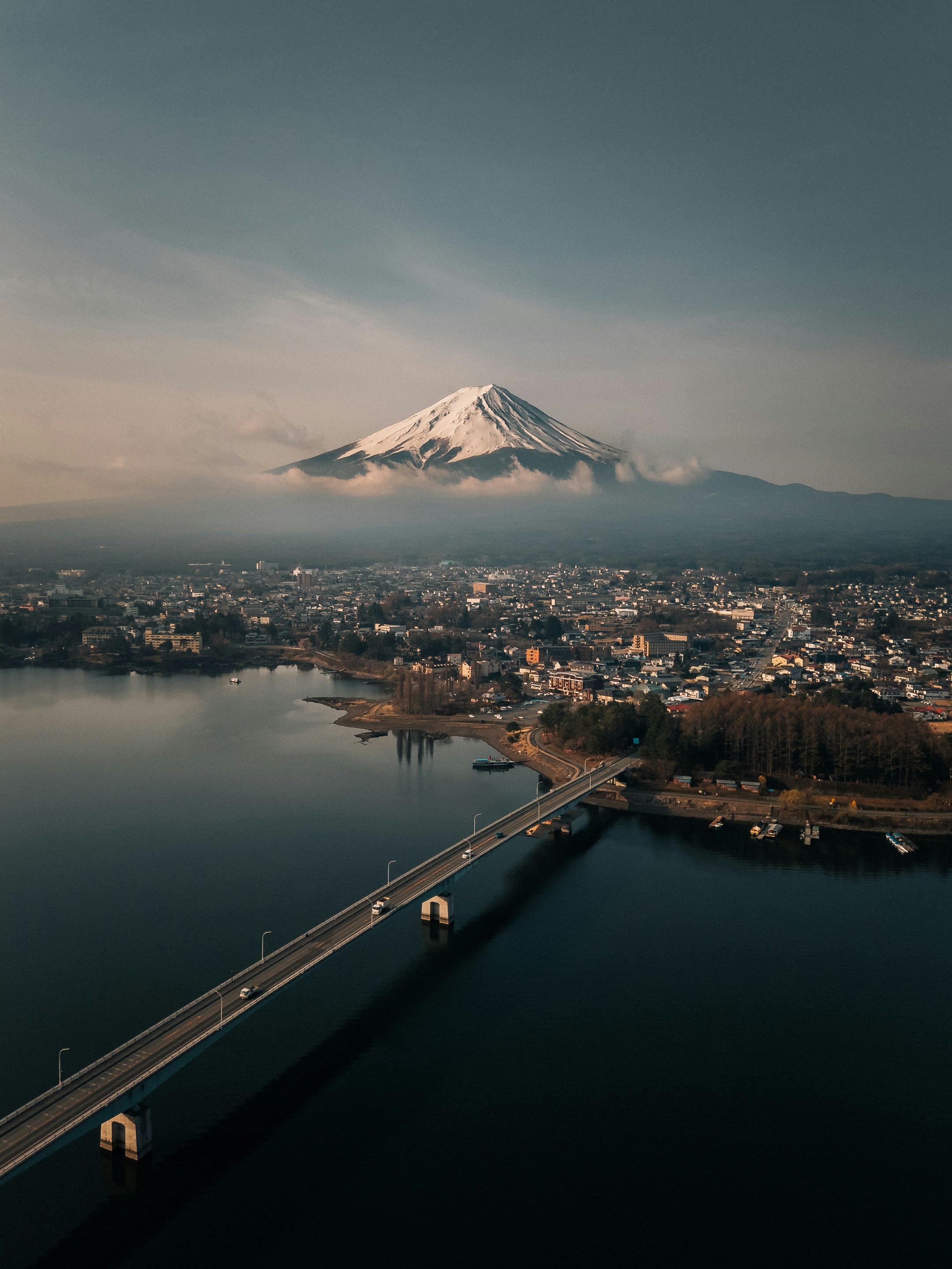 Check out my Instagram - @sebastiandugudae | Snow-capped mount fuji overlooks a town and lake.