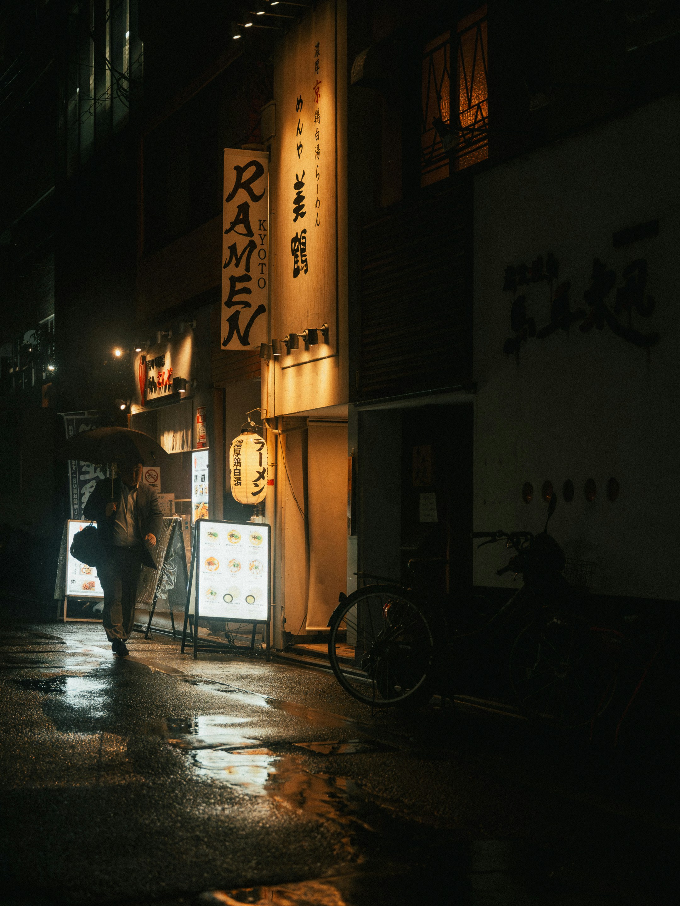 A person walks past a ramen shop at night. photo – Free Rain Image on ...