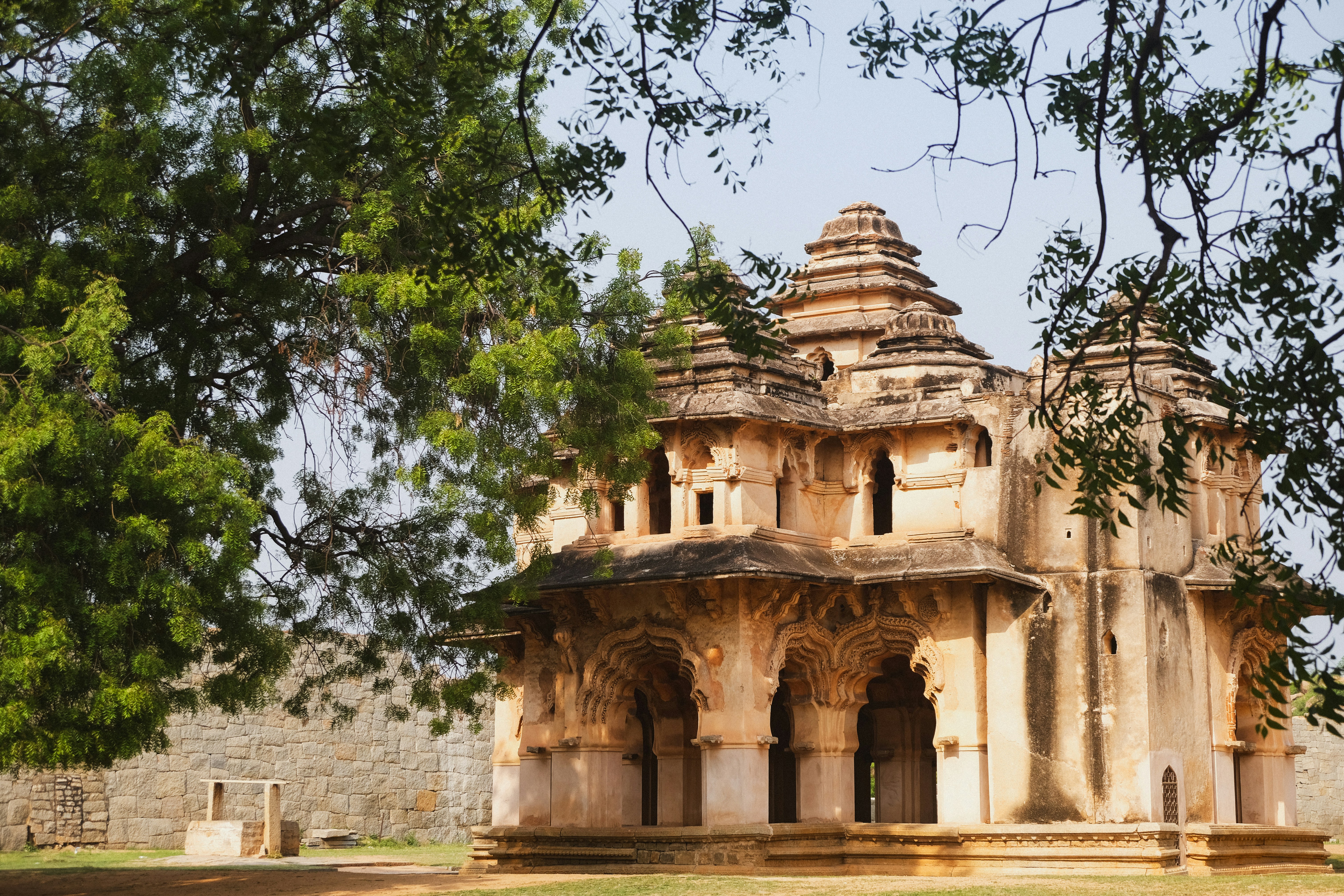 Ancient stone pavilion with ornate arches and tiered roof.
