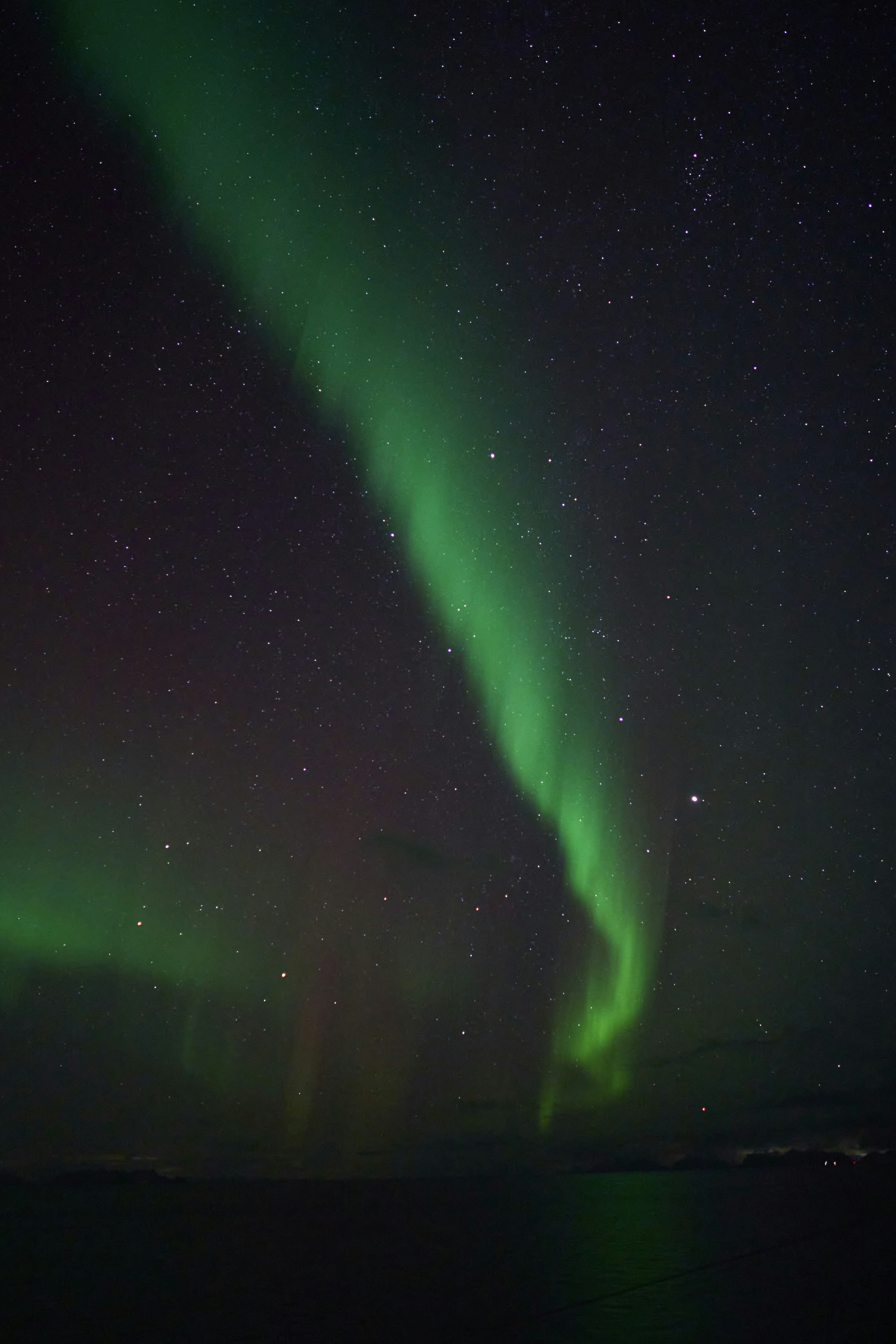 Green aurora borealis lights up the starry night sky.
