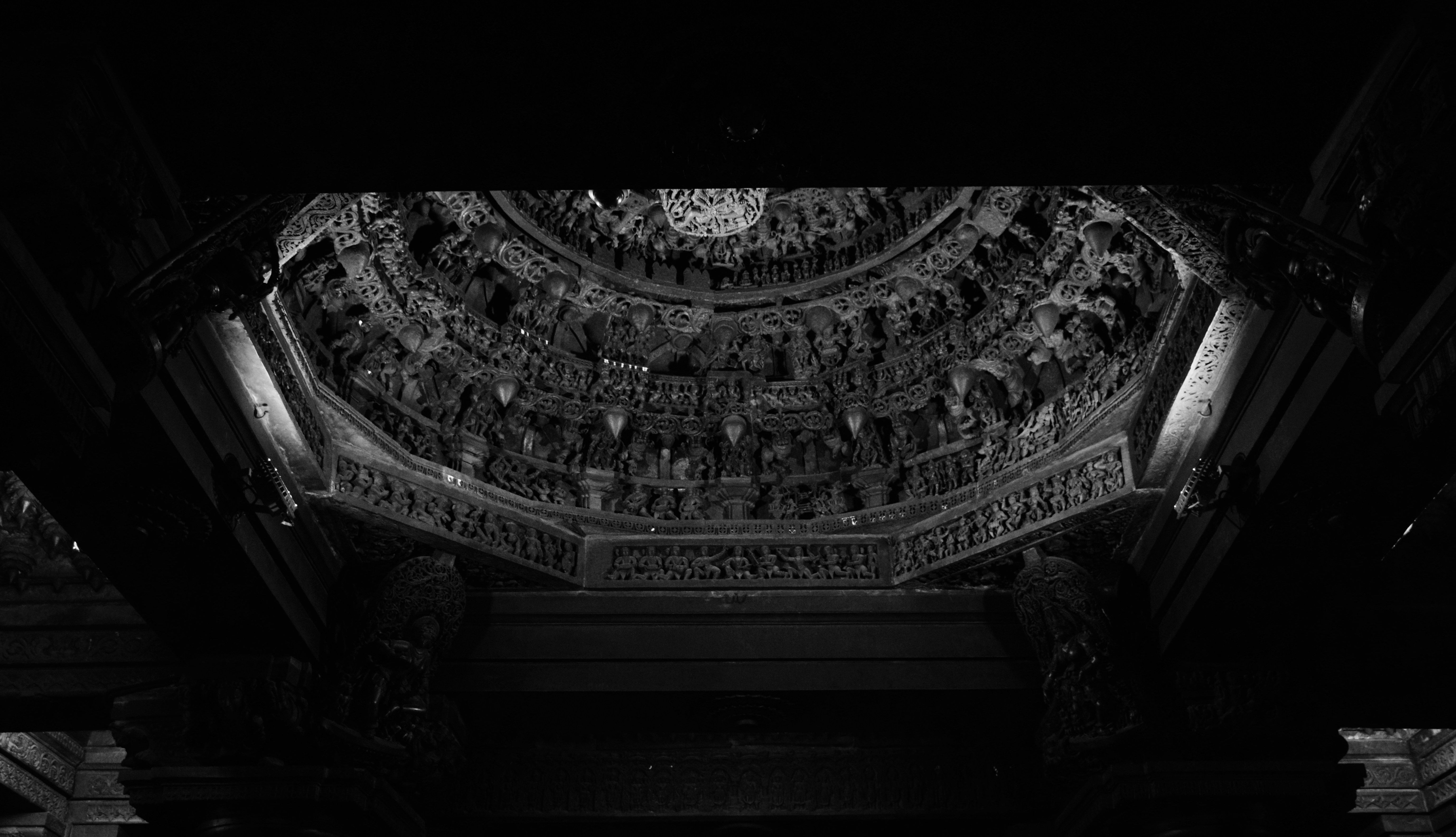 Ornate ceiling adorned with intricate carvings and sculptures, illuminated by subtle light in a dimly lit space.