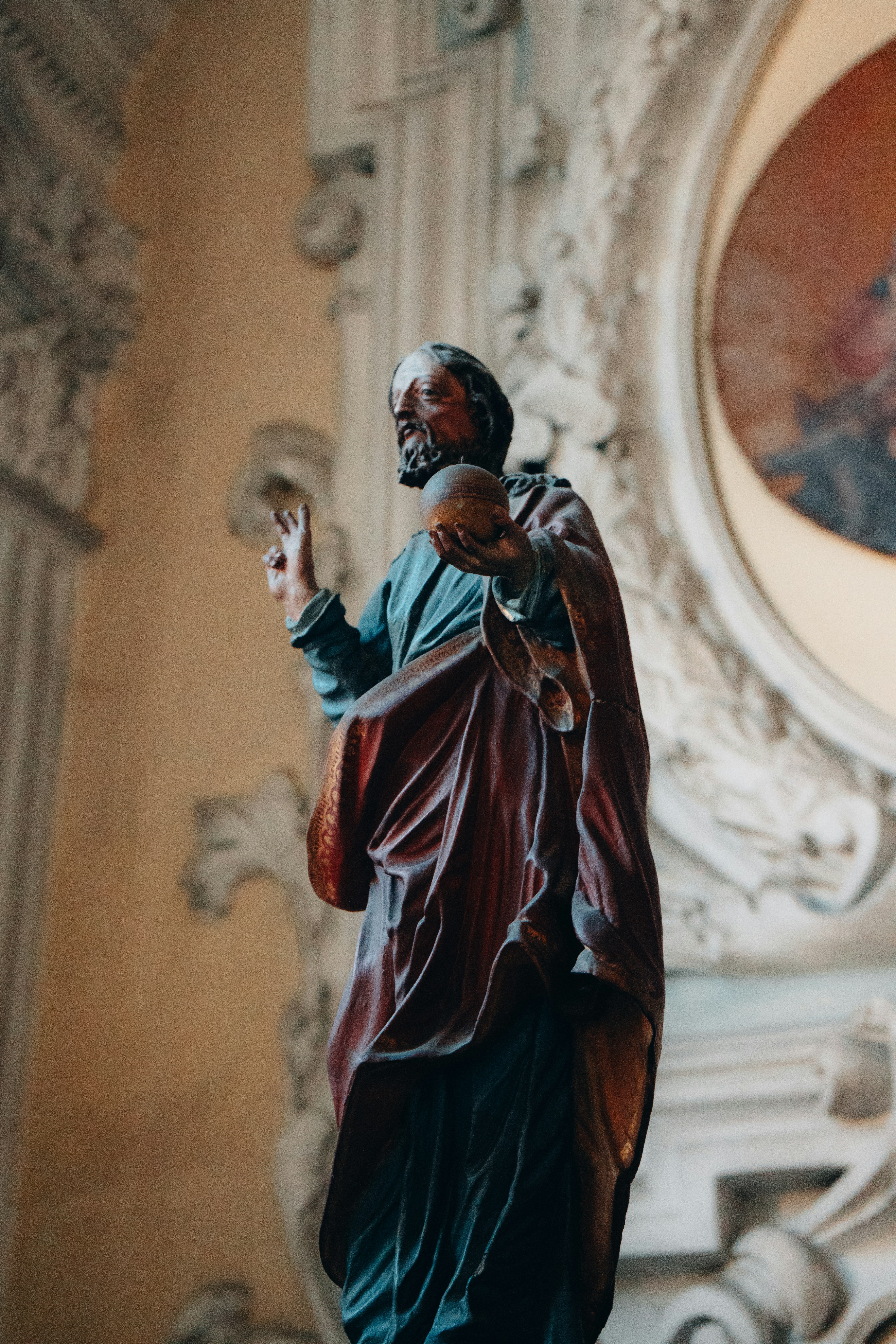 Intricate statue of a religious figure with a raised hand, set against a richly decorated backdrop.