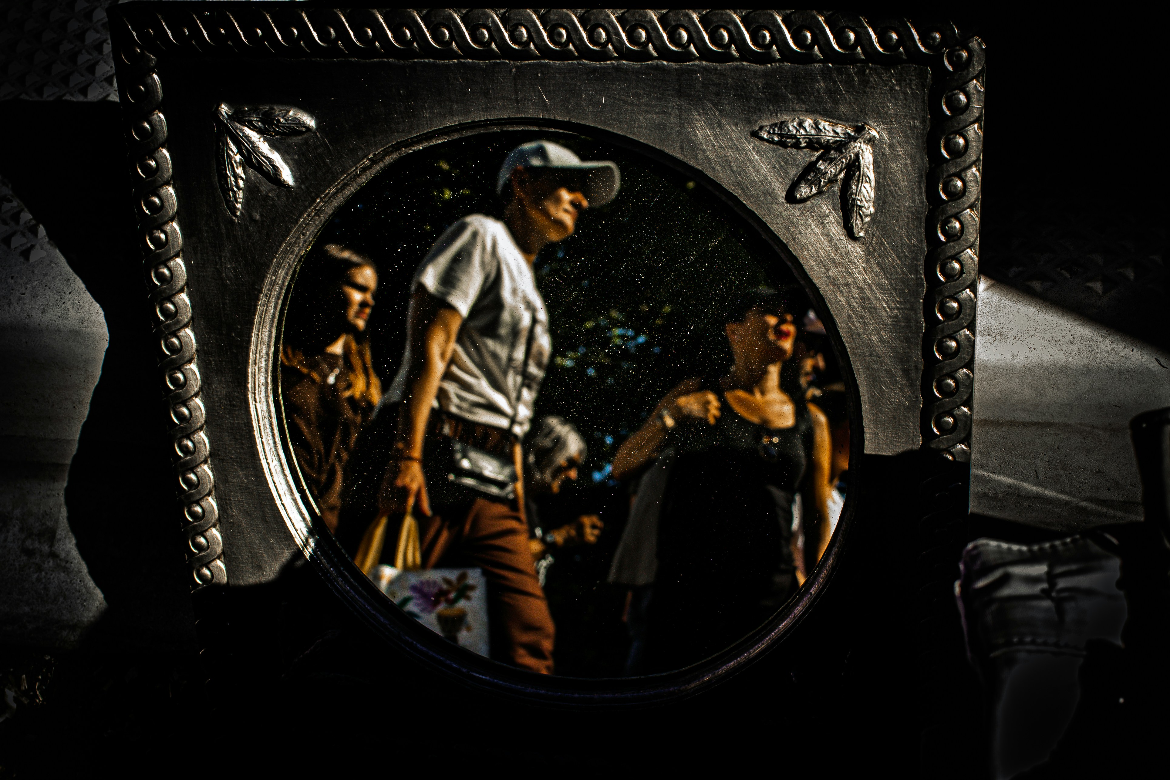 People reflected in an ornate, dark mirror.