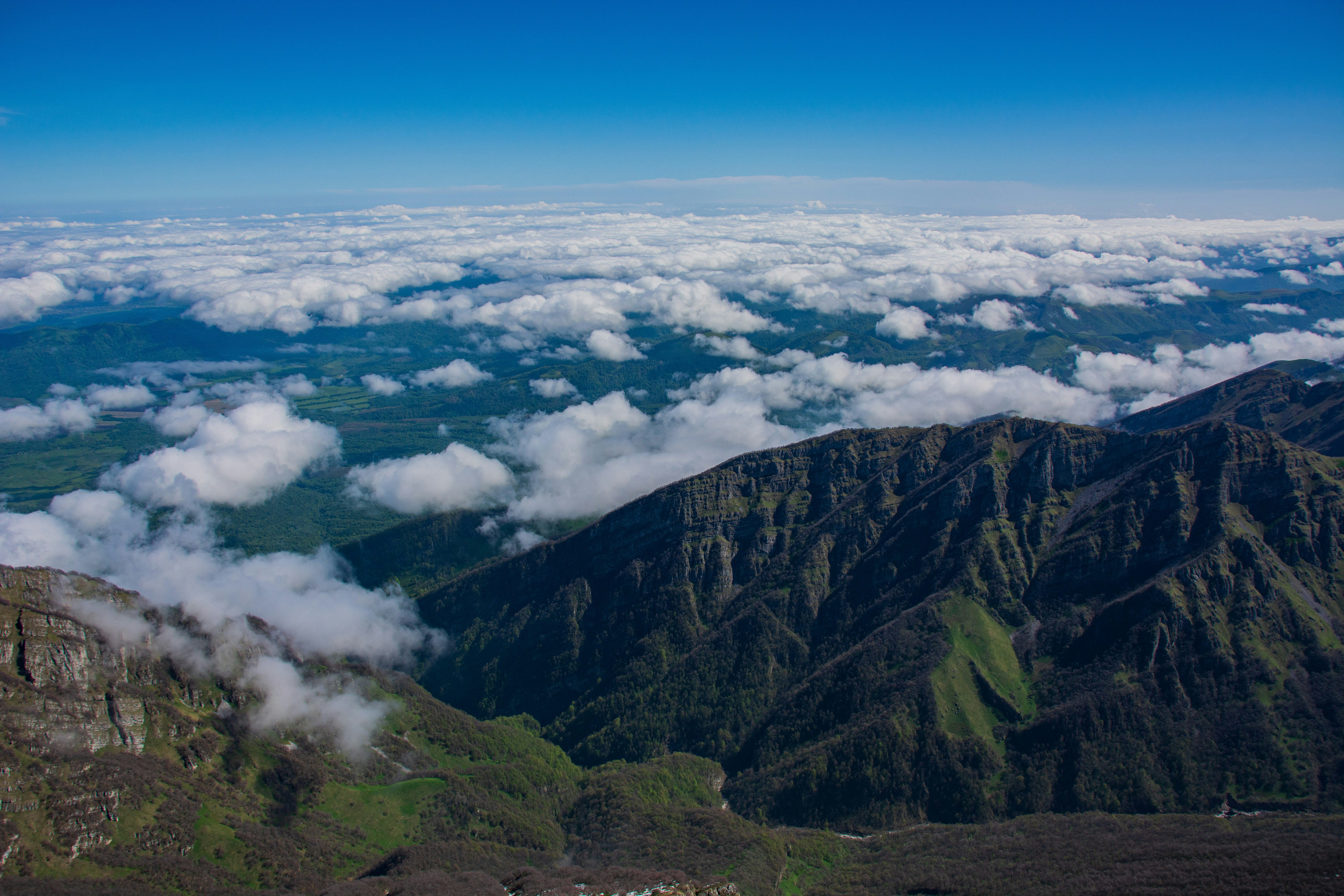 Clouds float over green mountains under a blue sky