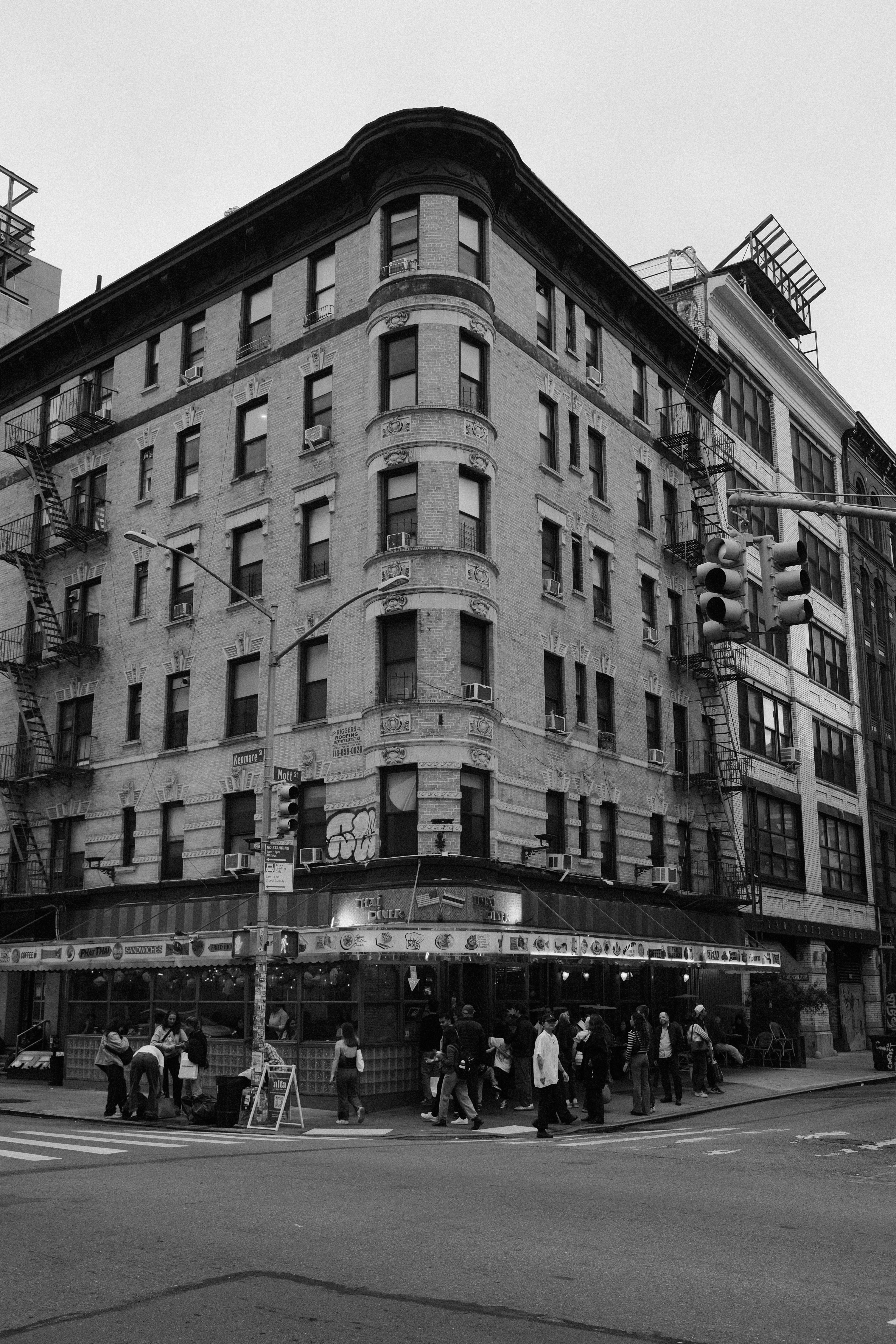 People gather outside a corner building in a city.