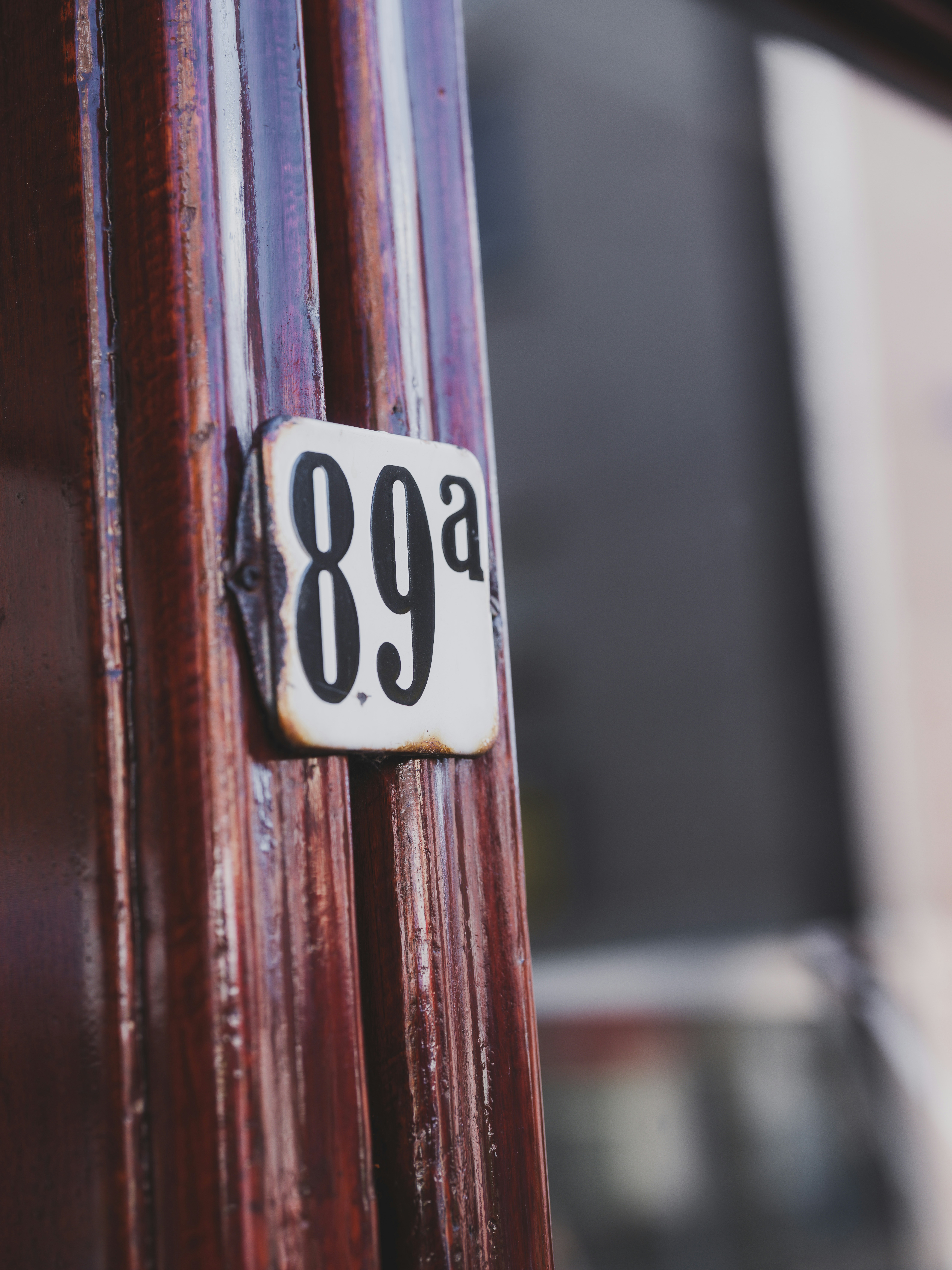89q on Weathered Lacquered Timber: Close-Up of a Door Plaque