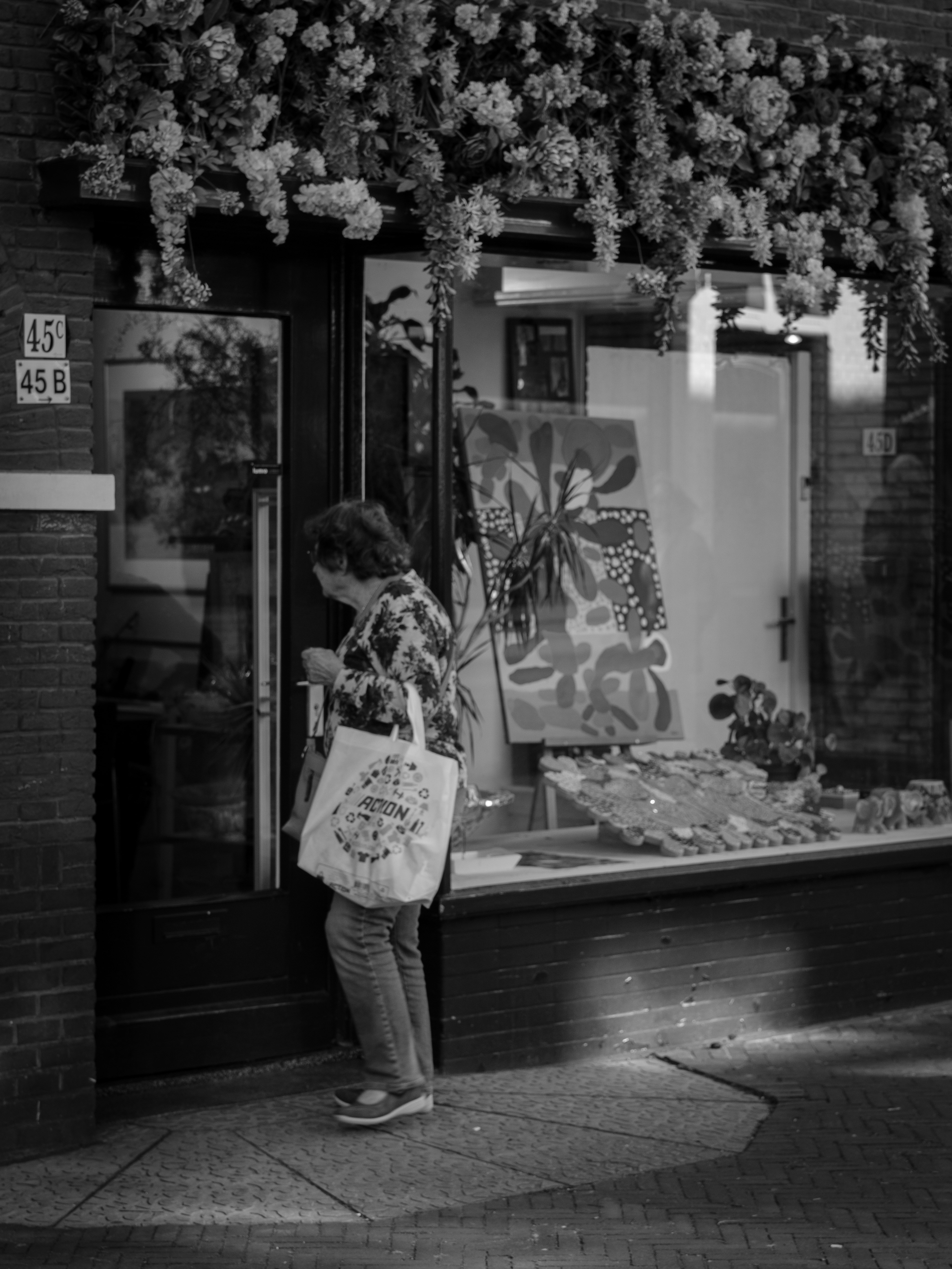 art store | Woman entering a shop with flowers above