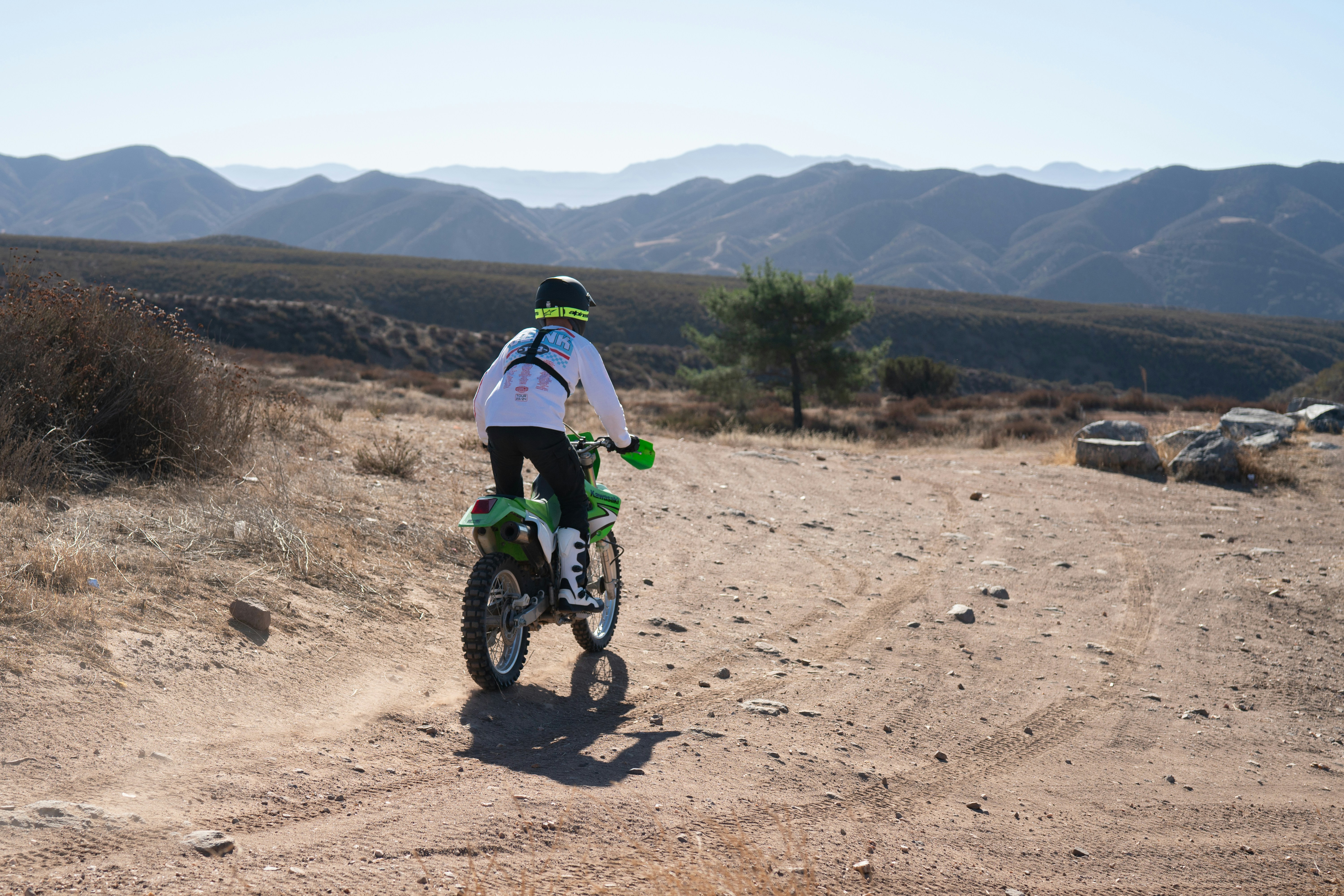 Person riding a dirt bike on a dry, dusty trail.
