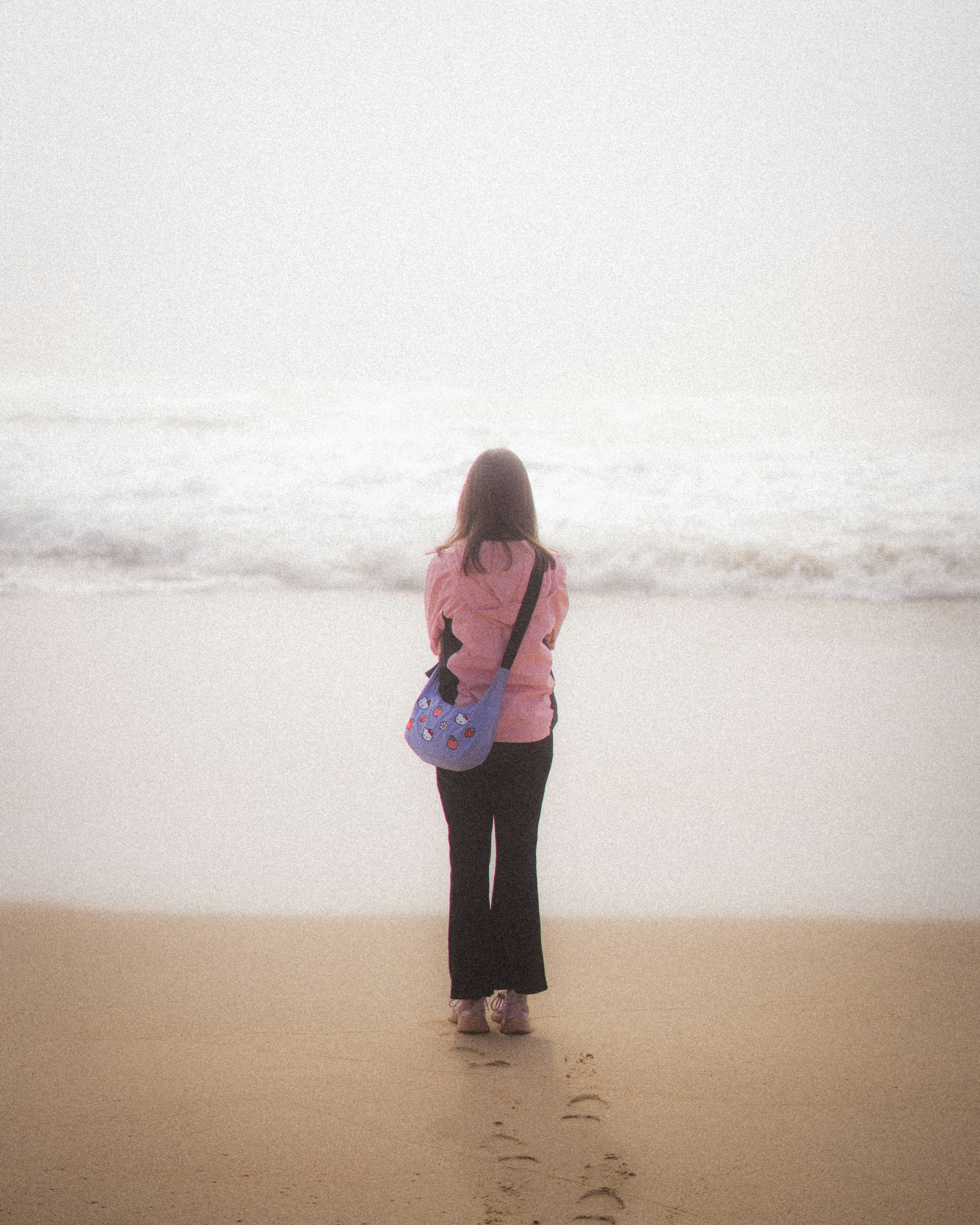 Woman standing on beach looking at ocean