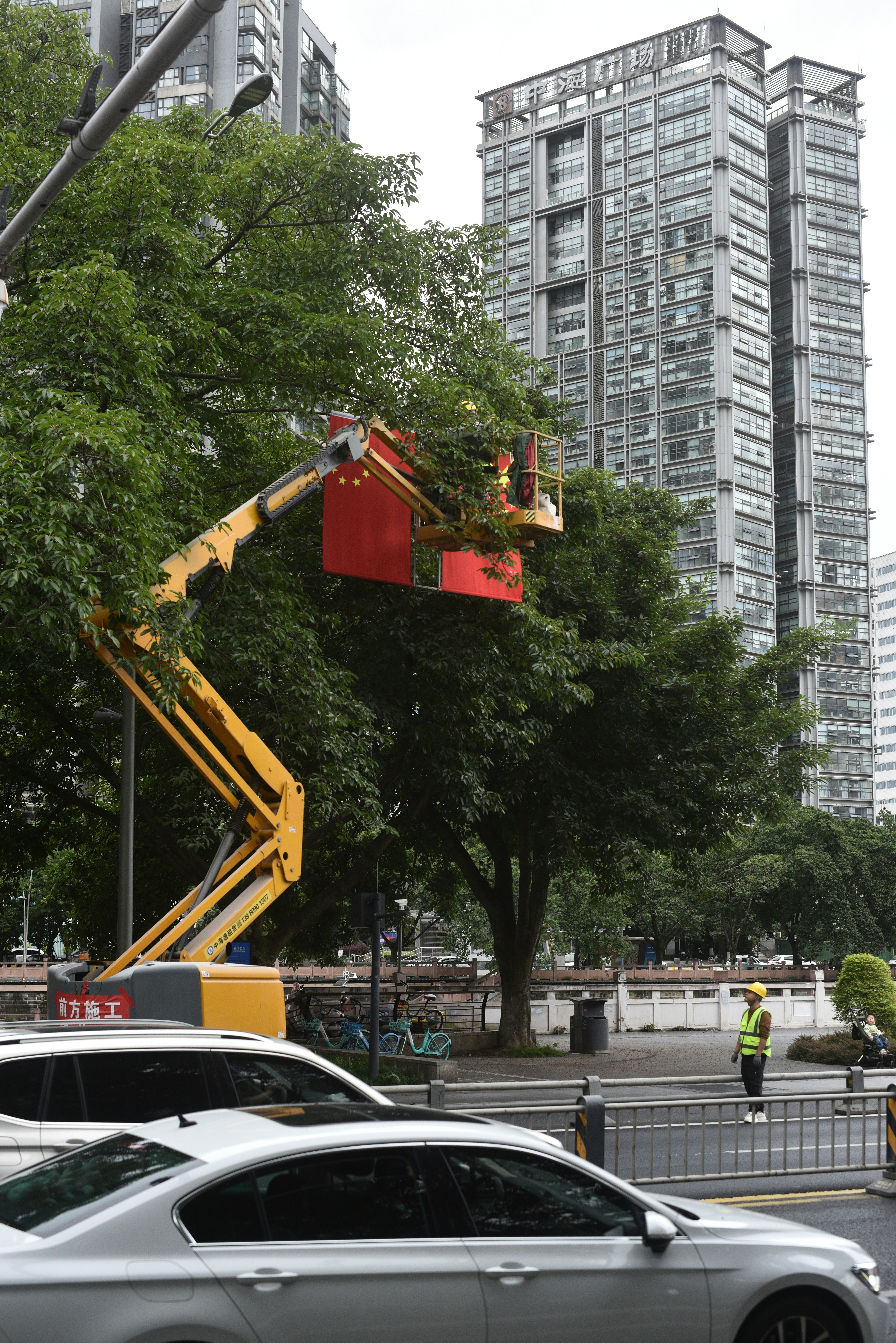 Cherry picker trimming trees with buildings behind.