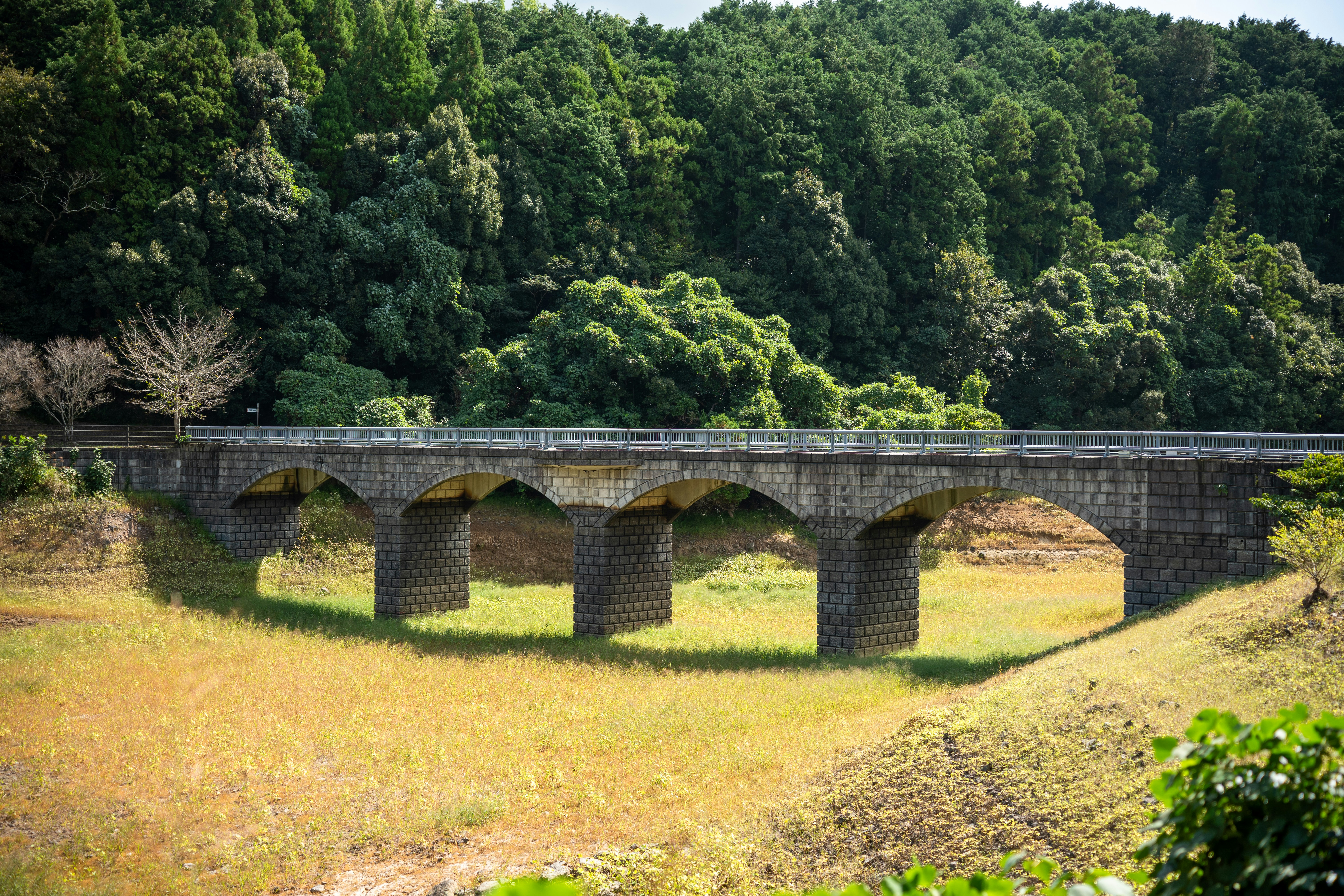 Stone arch bridge over a dry grassy field