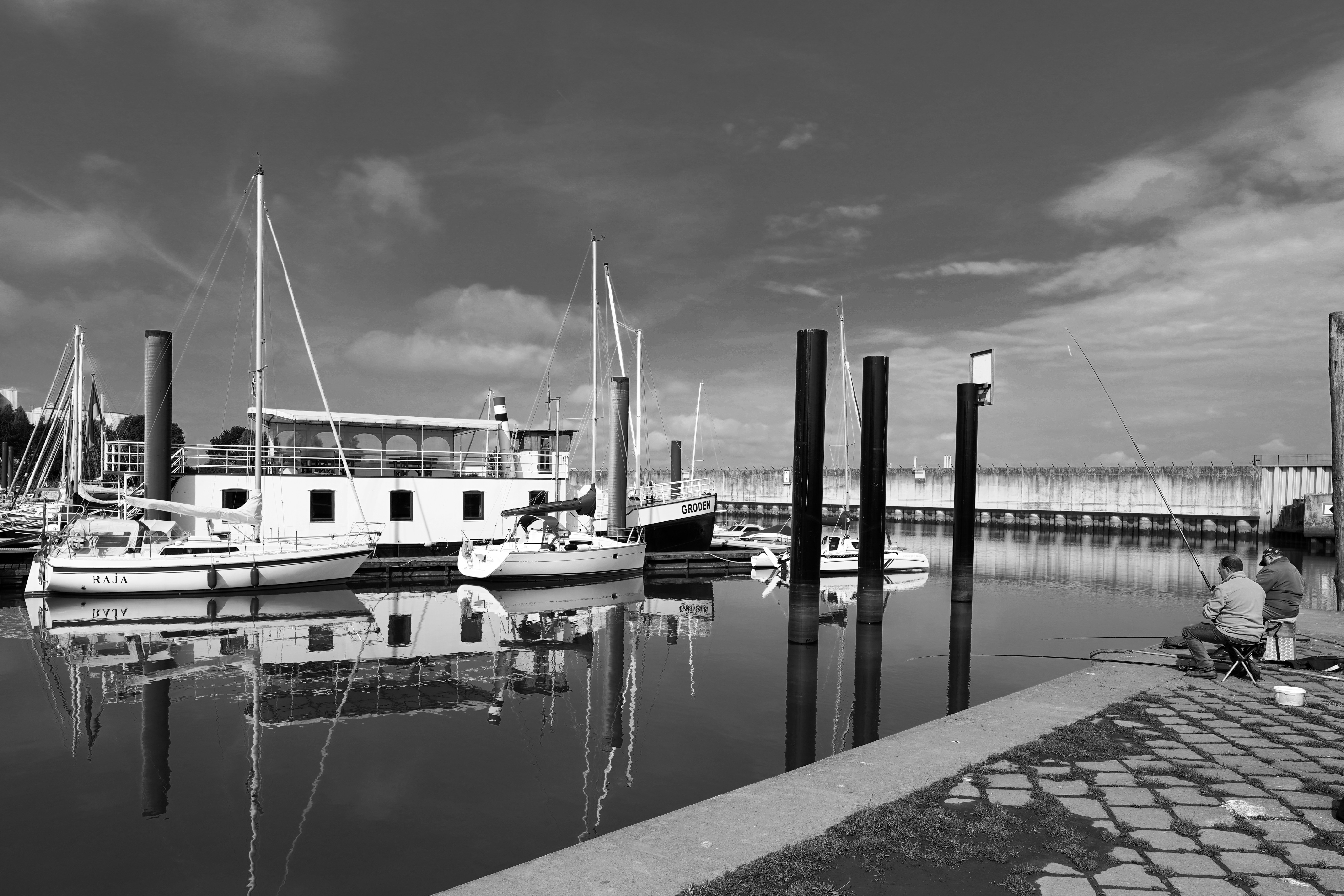 Sailboats docked in a calm harbor with reflections.