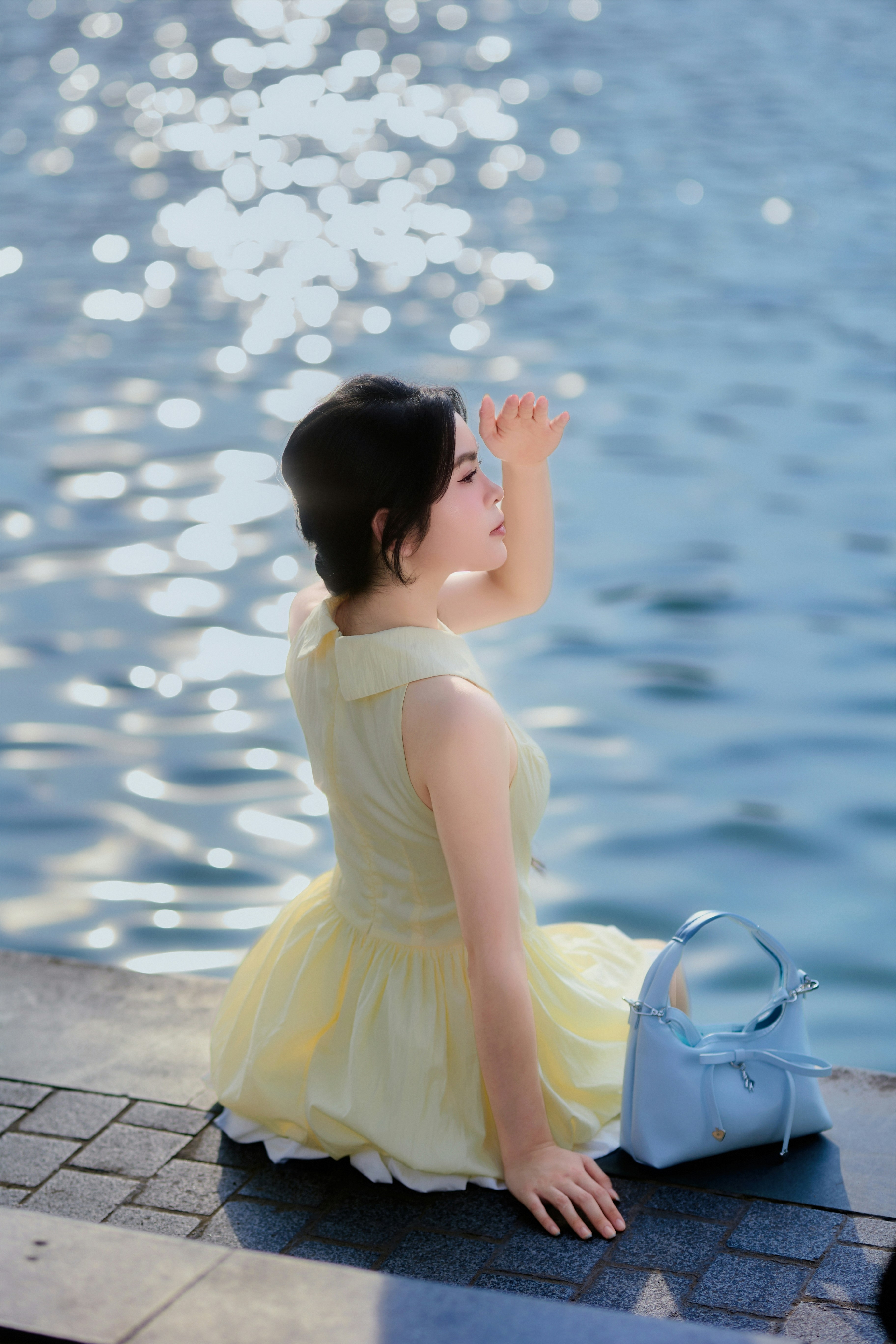A beautiful young woman strolls through the autumn of Hanoi. | Woman in yellow dress looking at the sunlit water