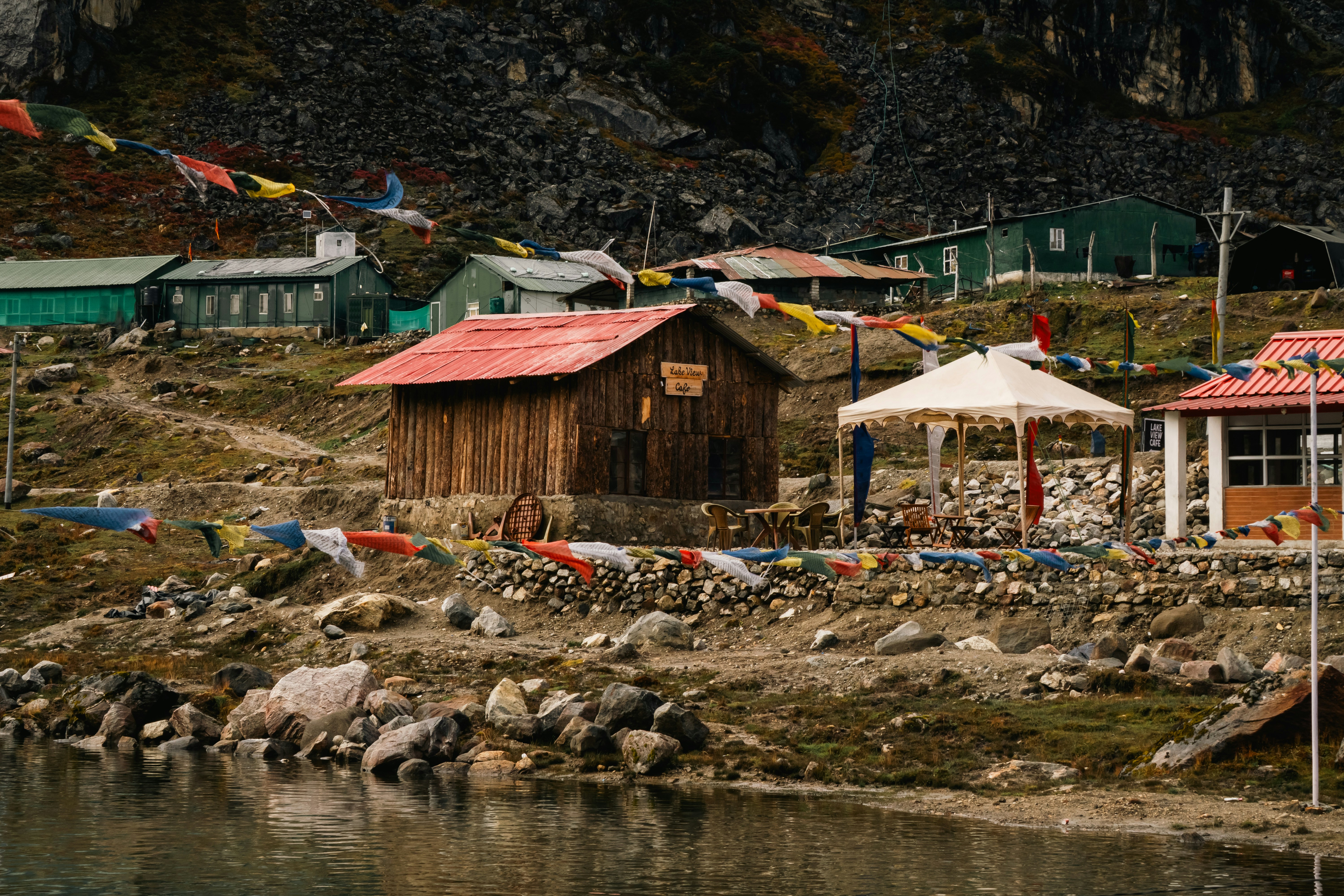 Picturesque Cafe by the Lake at 14000ft | Small village with colorful prayer flags and buildings.