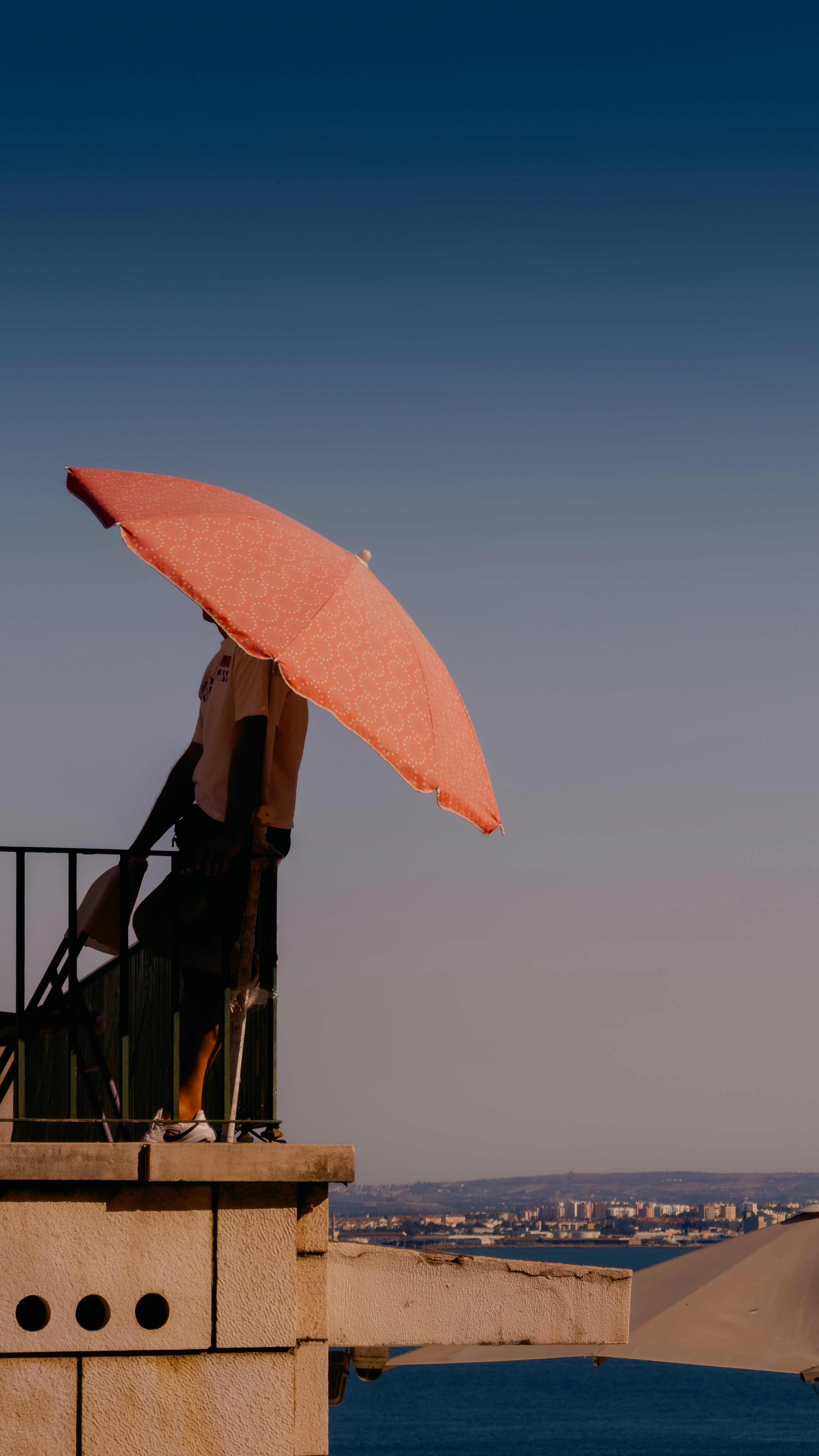 Person with umbrella on balcony overlooking ocean