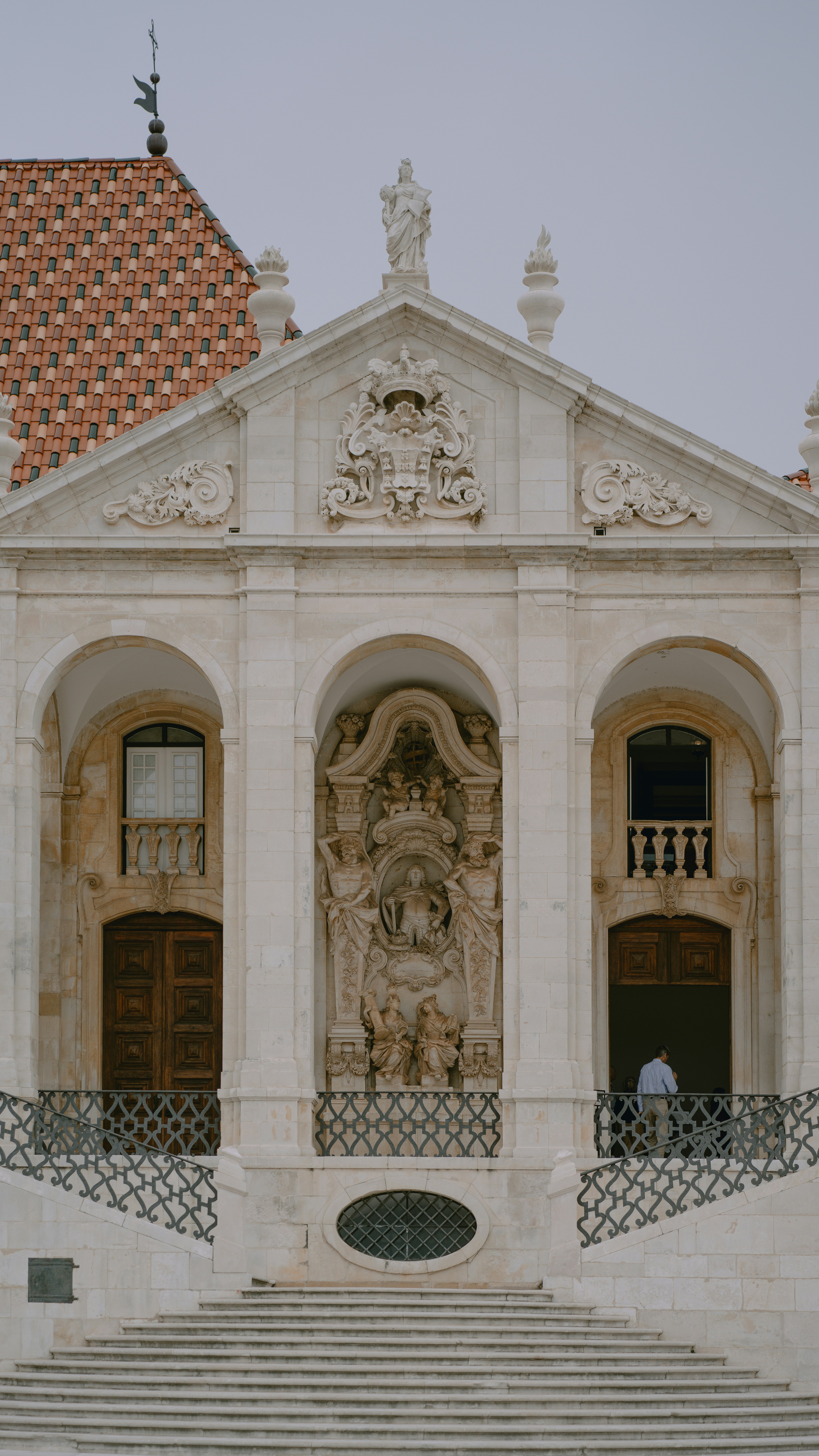 Man stands on balcony of ornate stone building